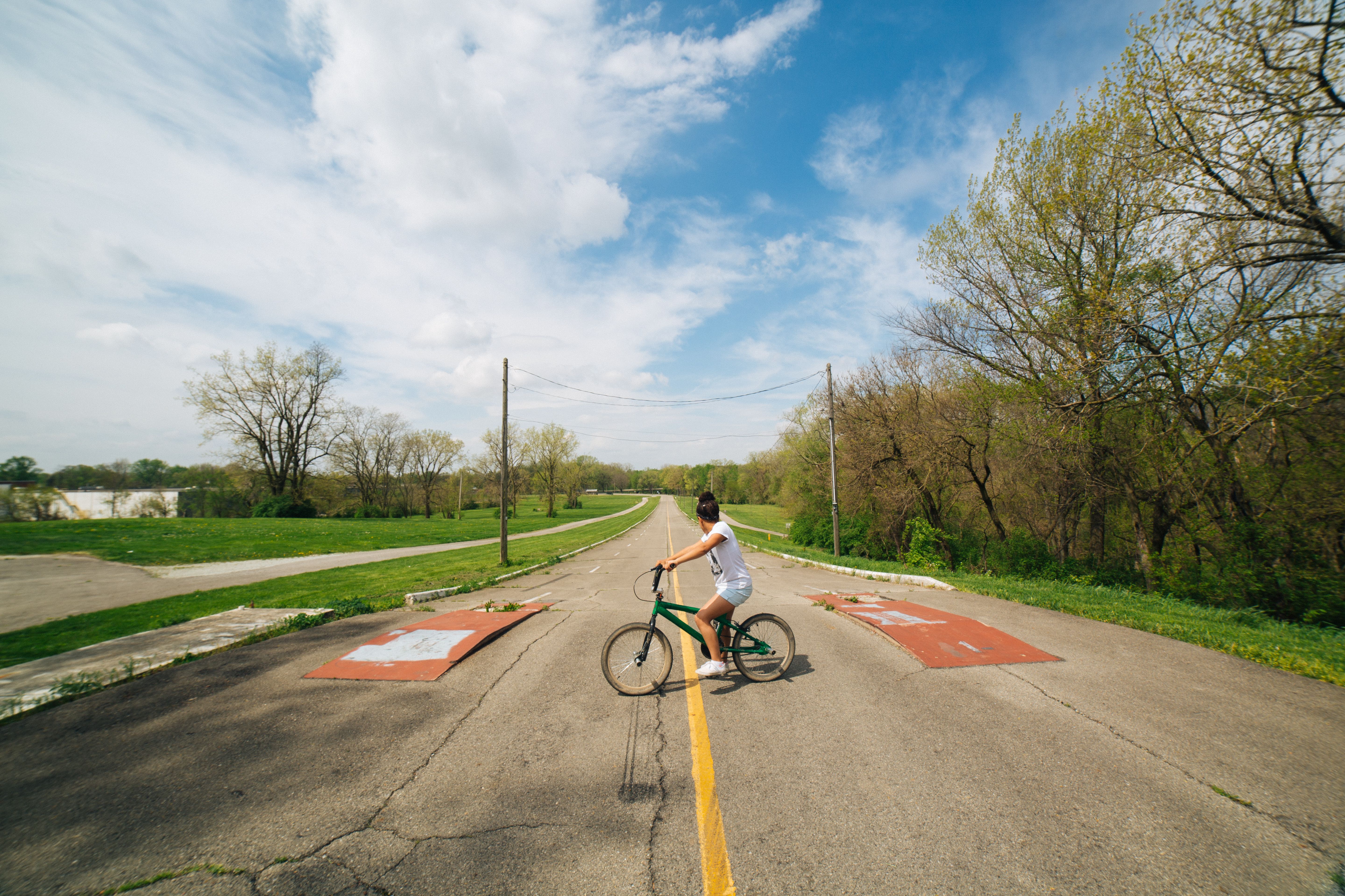 Cyclist crossing road on bicycle on sunny day · Free Stock Photo