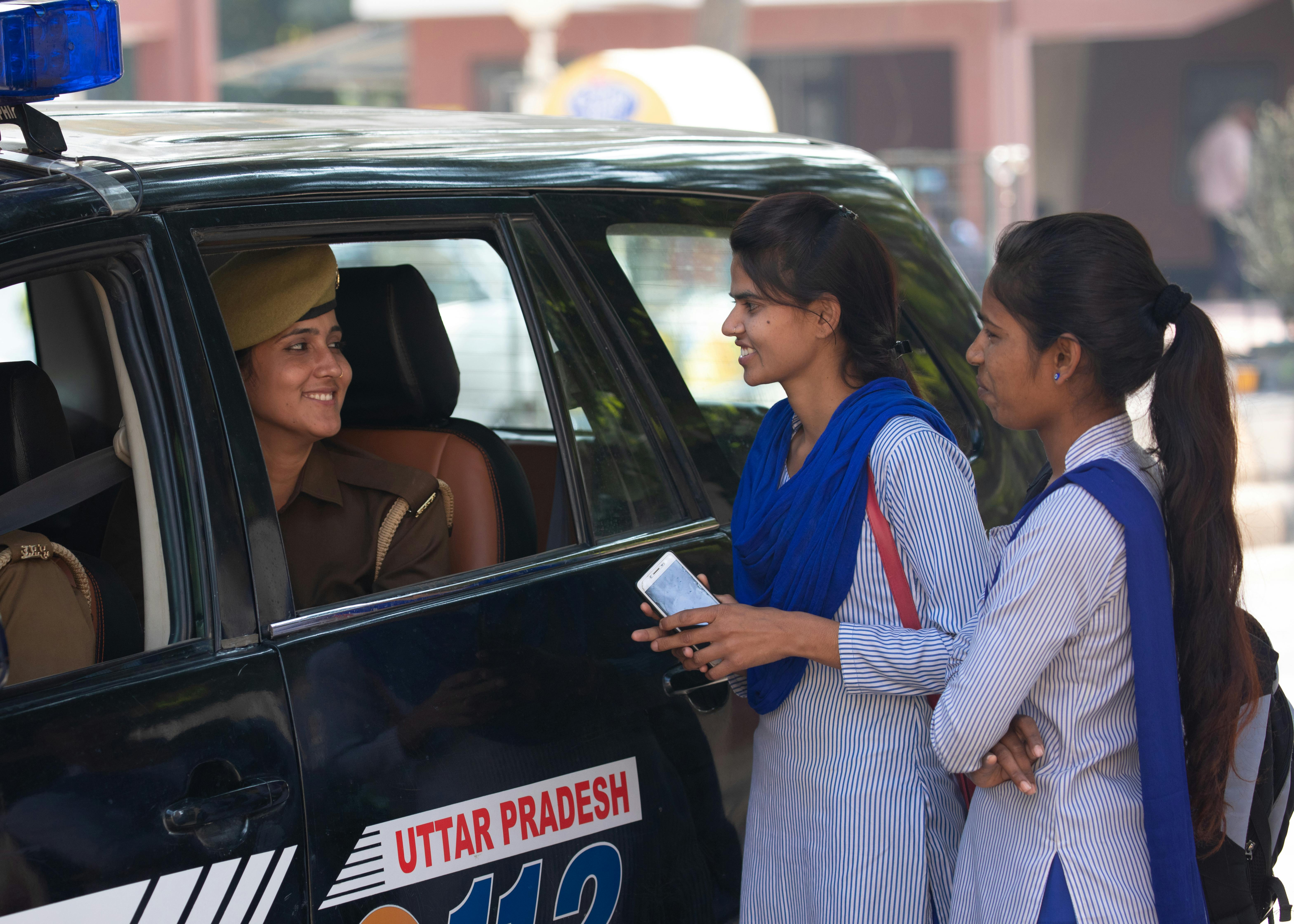 A Policewoman in a Police Car Smiling at Young Women · Free Stock Photo