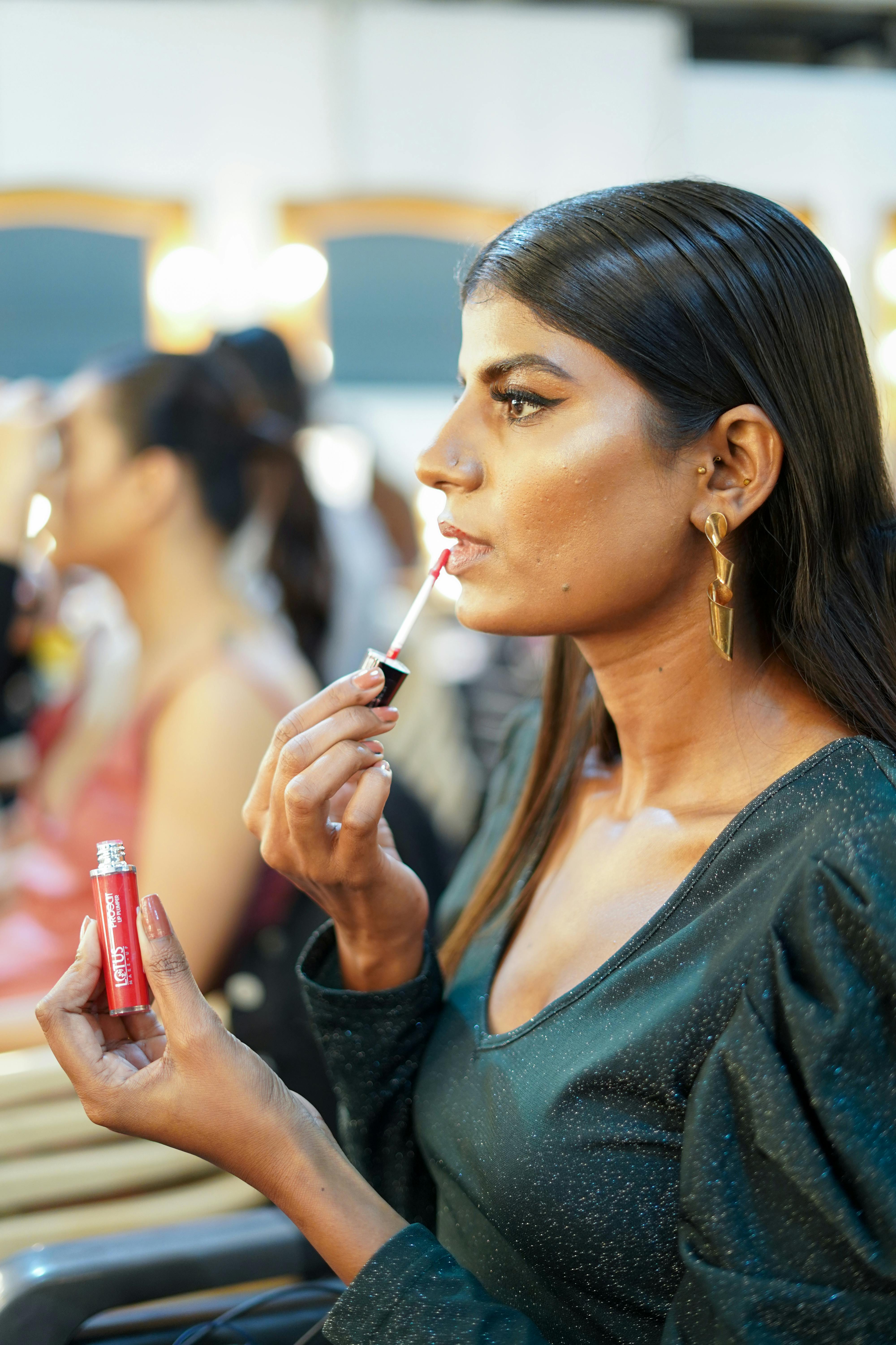 Trendy ethnic model applying lip gloss in dressing room · Free Stock Photo