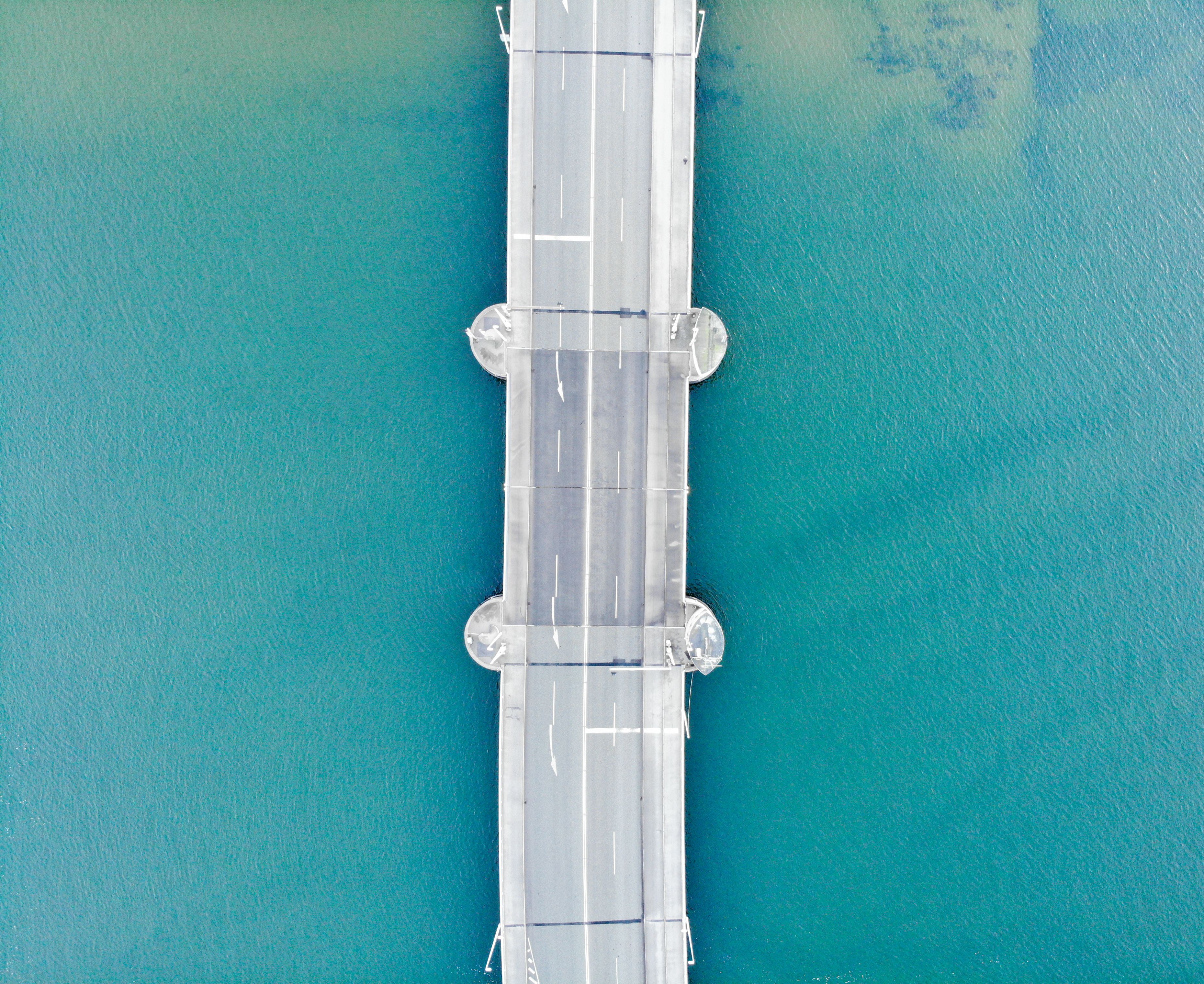 Drone view of modern asphalt bridge over blue water · Free Stock Photo