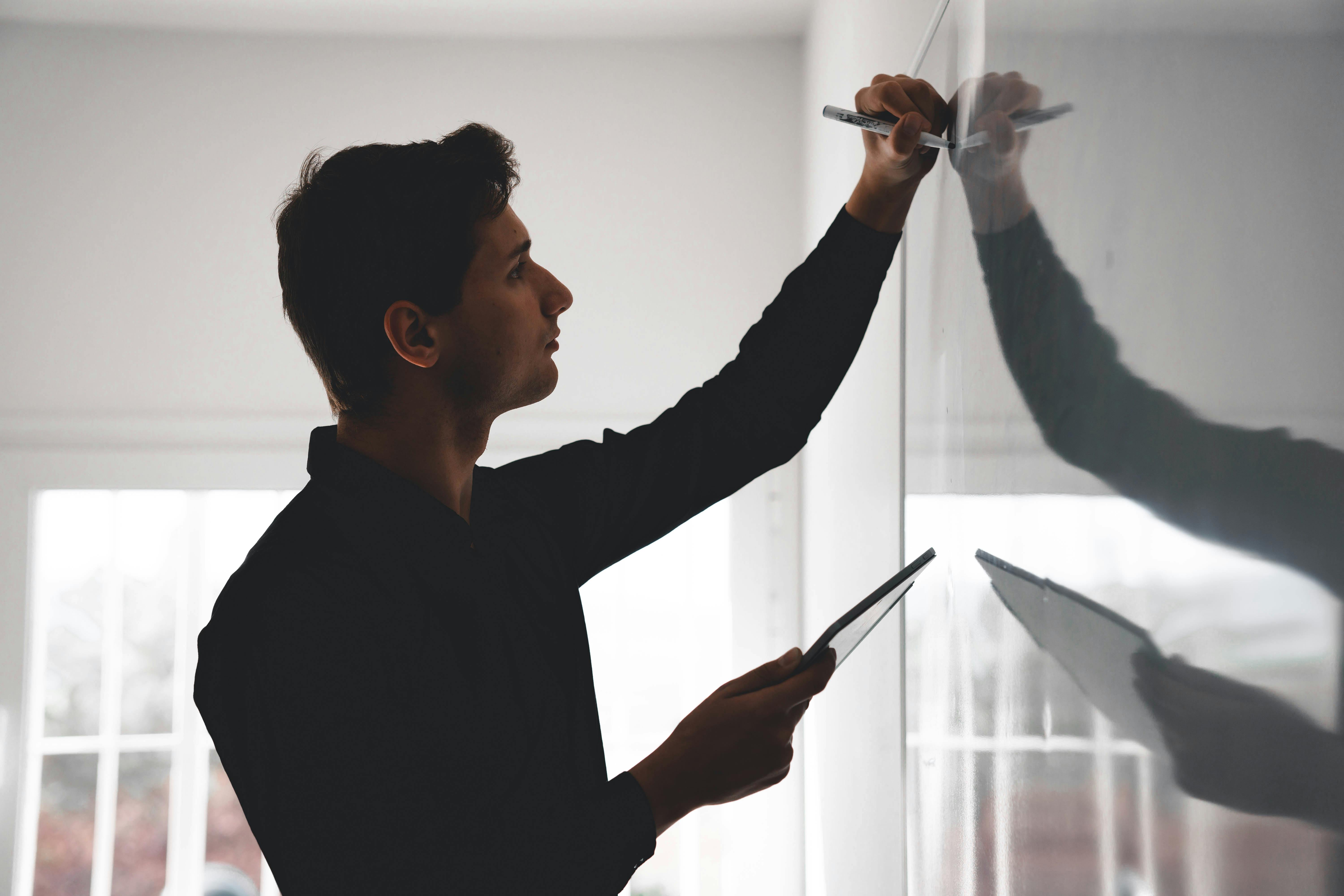 A Woman in a Blazer Writing on a Whiteboard · Free Stock Photo