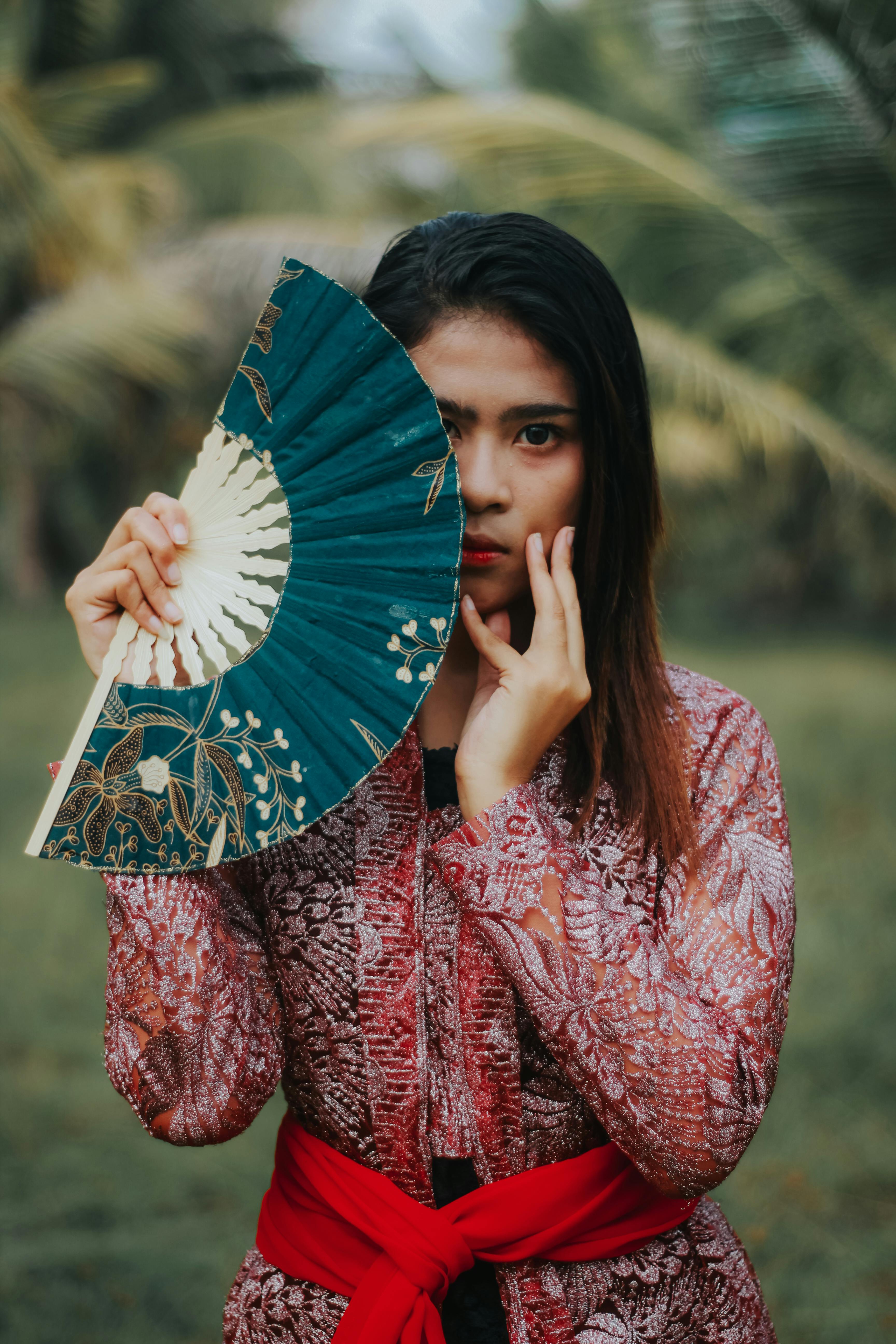 A Woman Holding a Hand Fan · Free Stock Photo