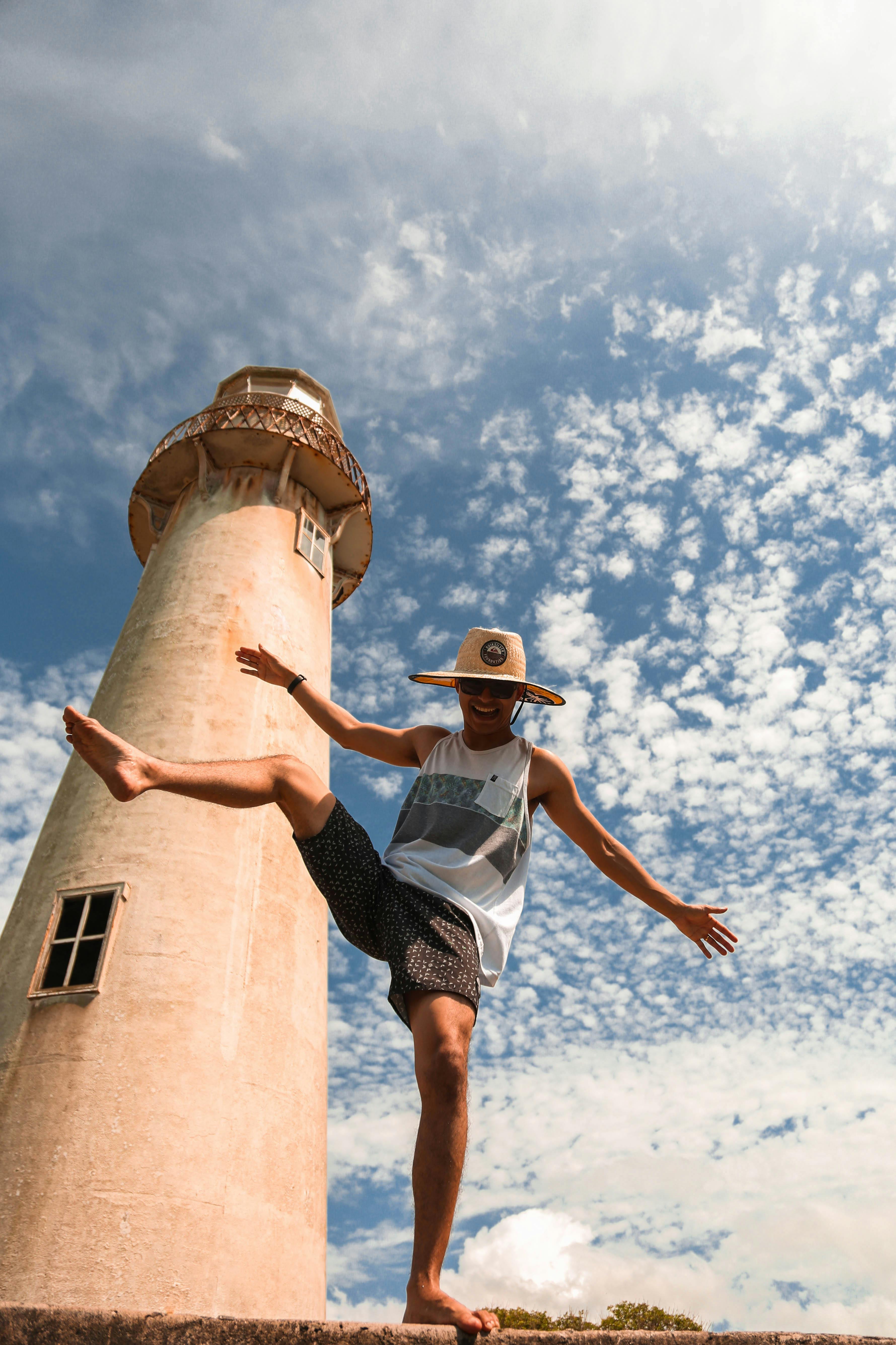 Unrecognizable tourist dancing near old lighthouse under cloudy sky ...