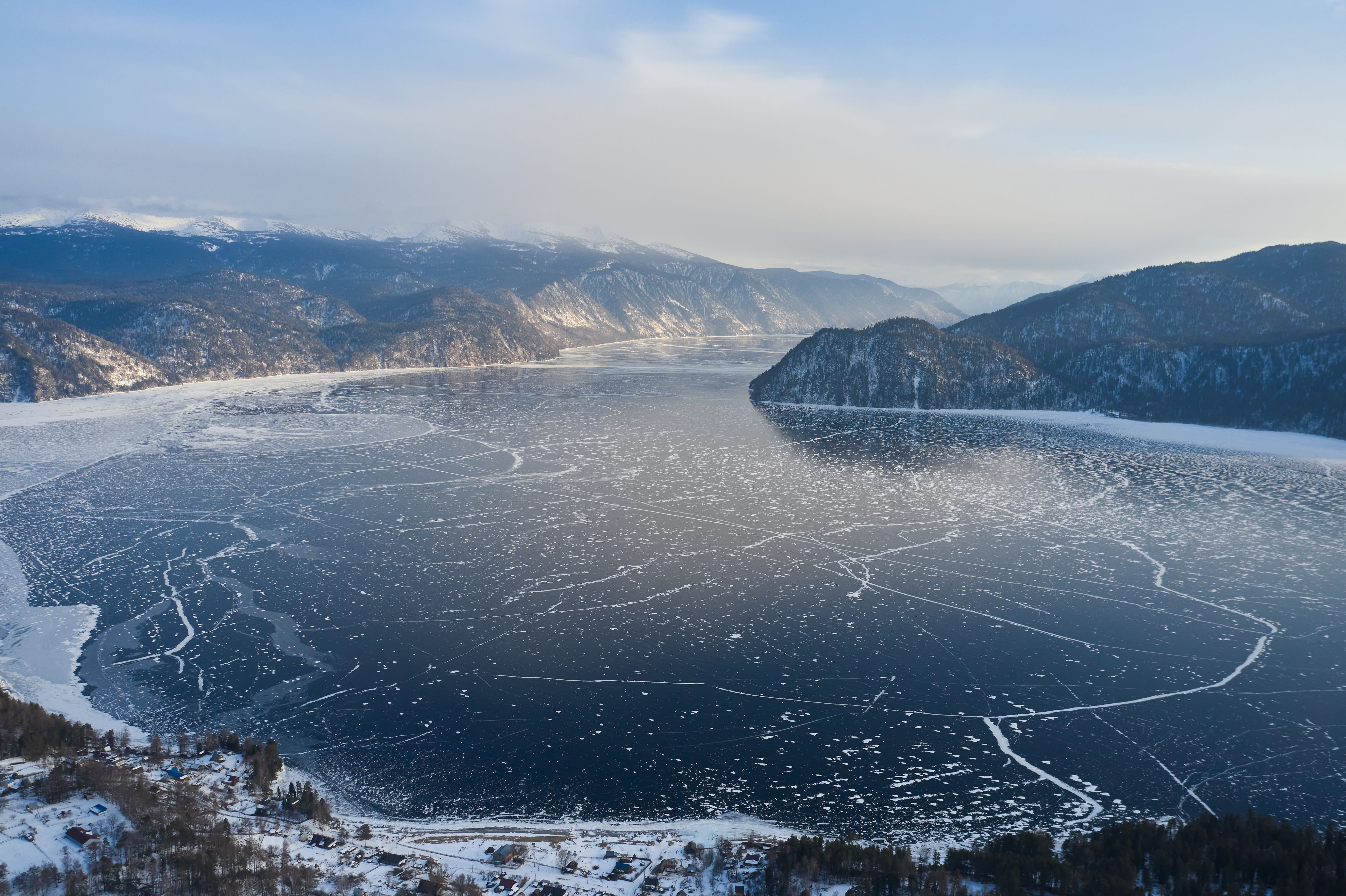 Frozen lake surrounded with wooded mountains in snowy winter · Free ...