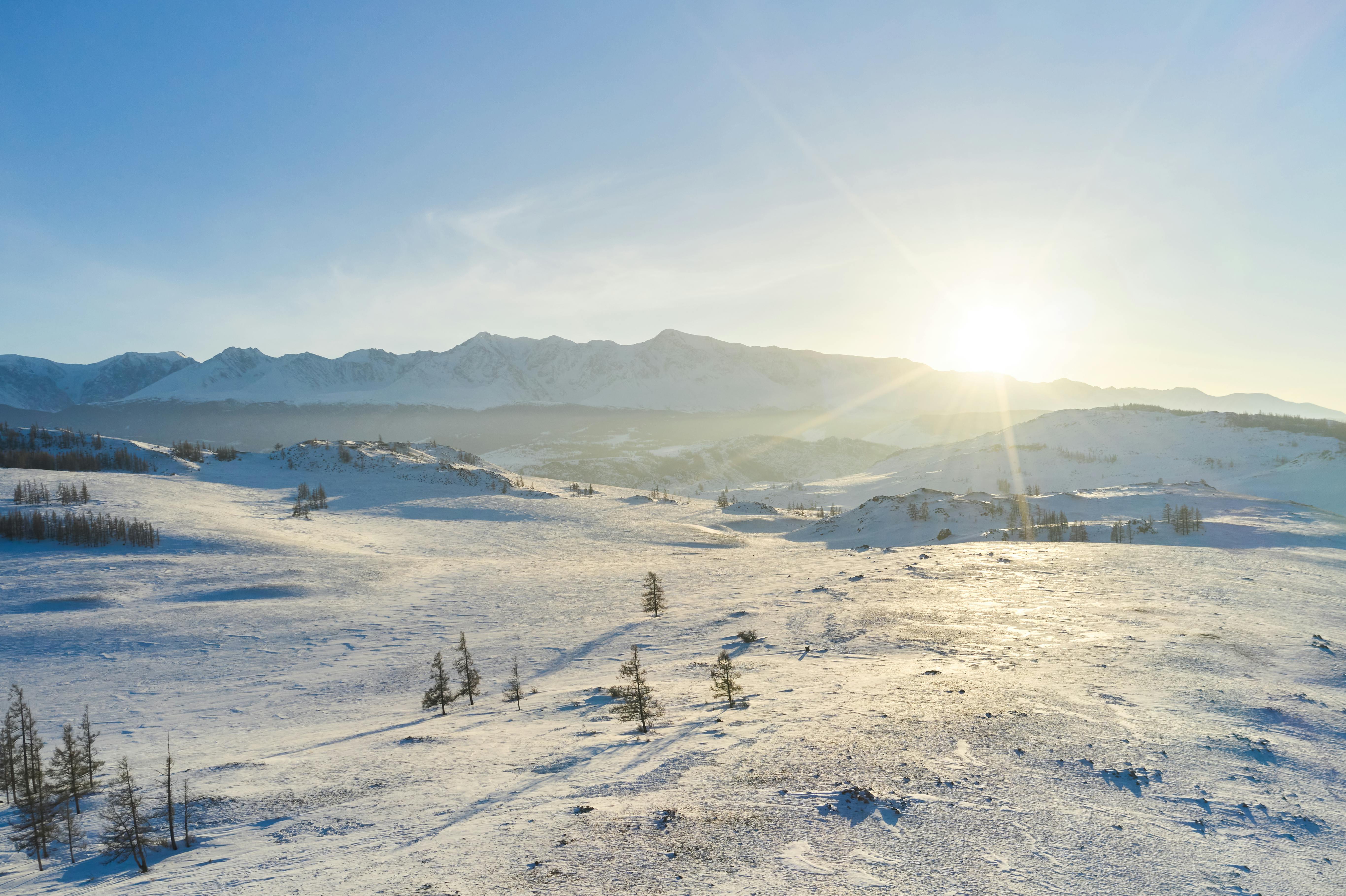 Snowy terrain against mountains in back lit · Free Stock Photo