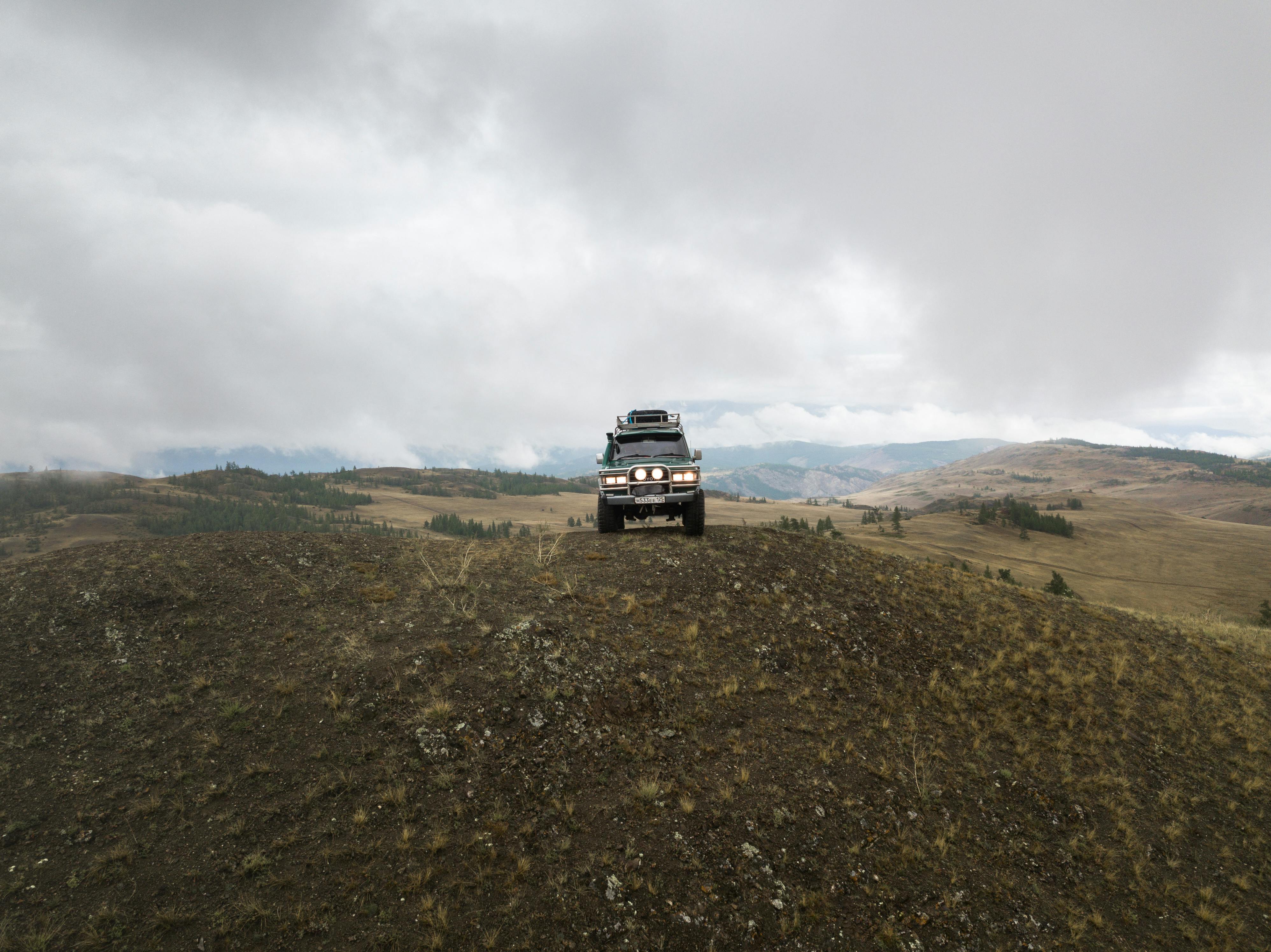 Old car parked on hill near mountains in valley · Free Stock Photo