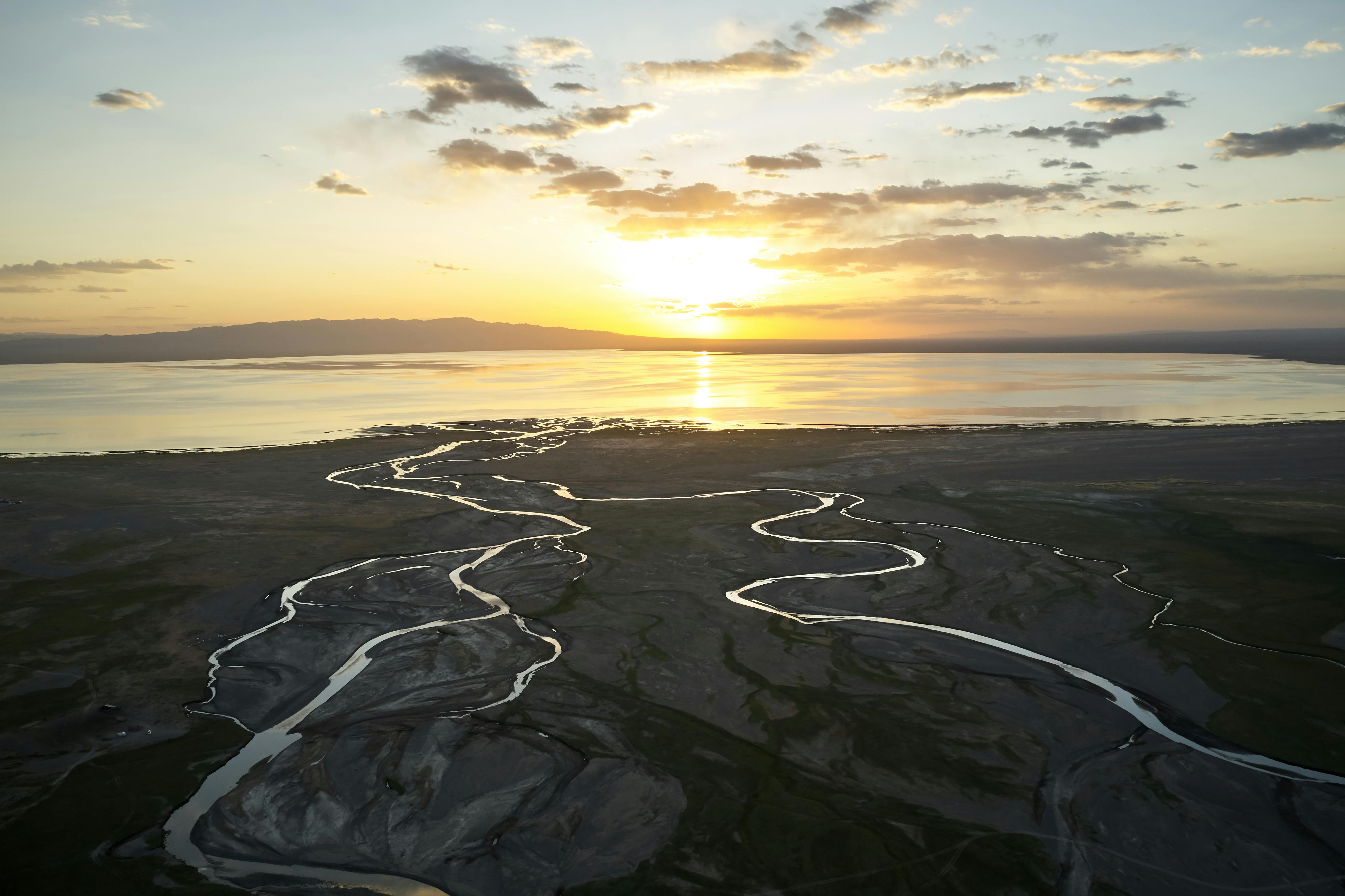 Big lake with river inflows near mountains at sunset · Free Stock Photo