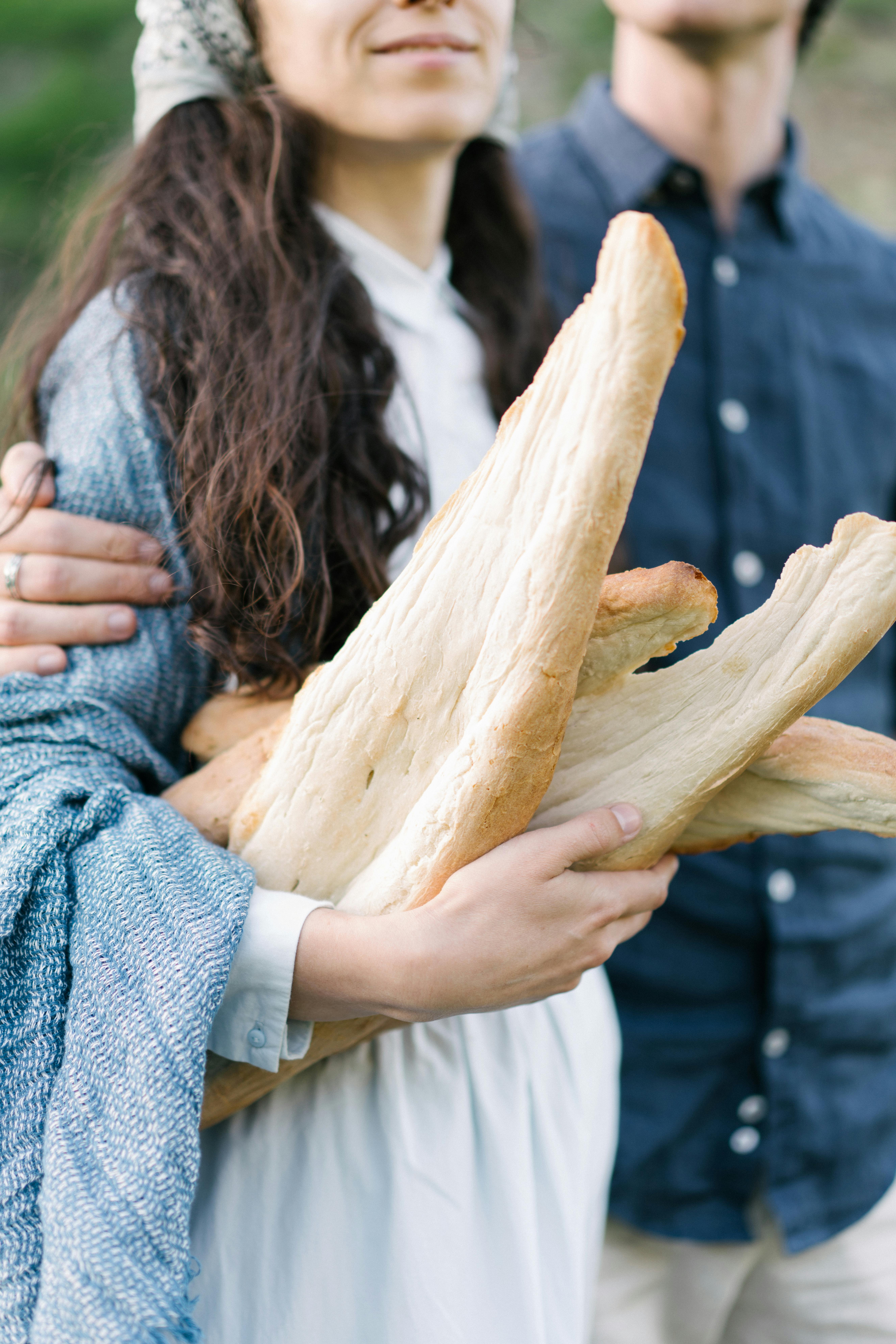 Crop couple carrying loaf of fresh bread · Free Stock Photo