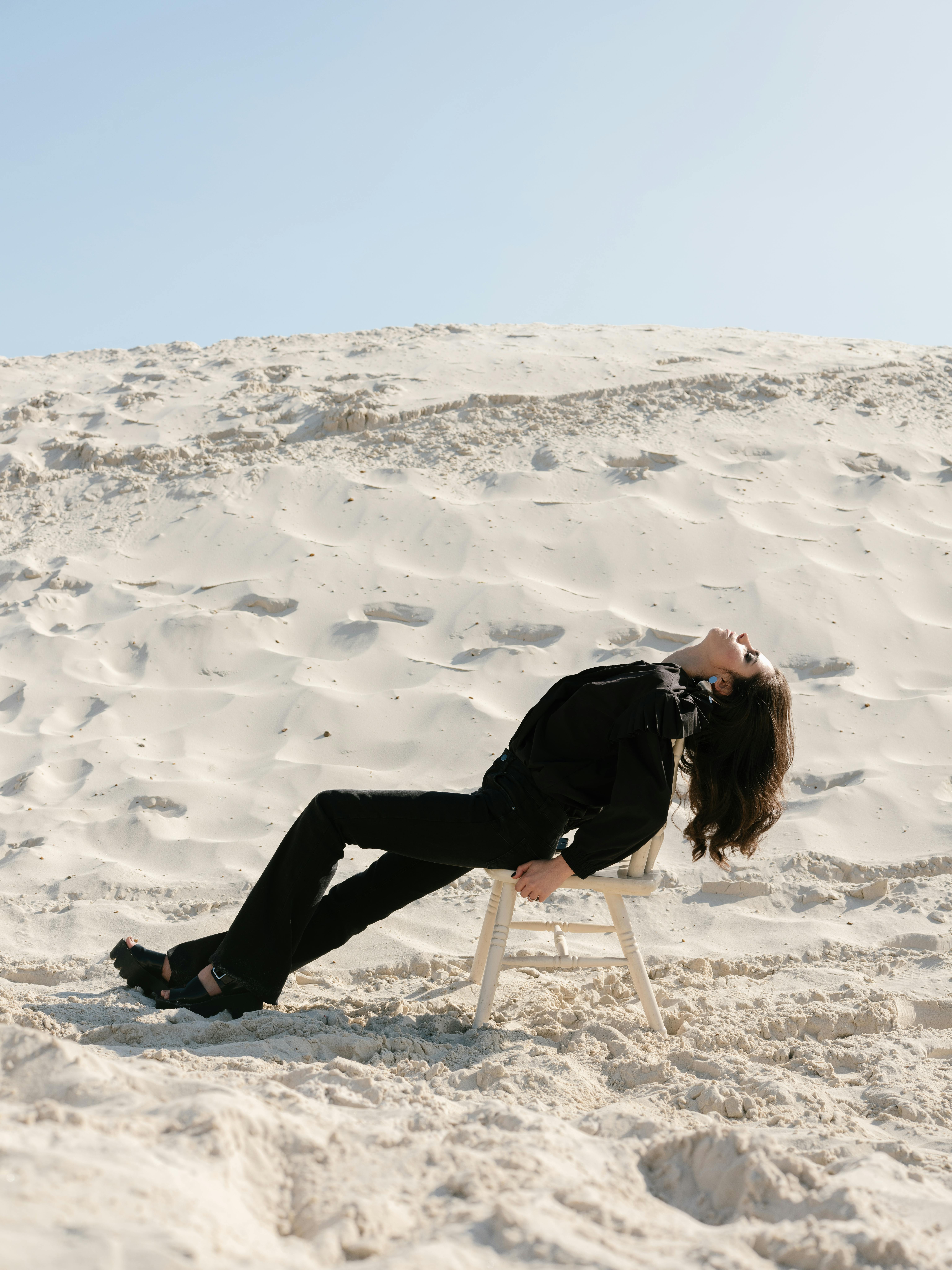 Woman sitting with tilted head back near sandy hill · Free Stock Photo
