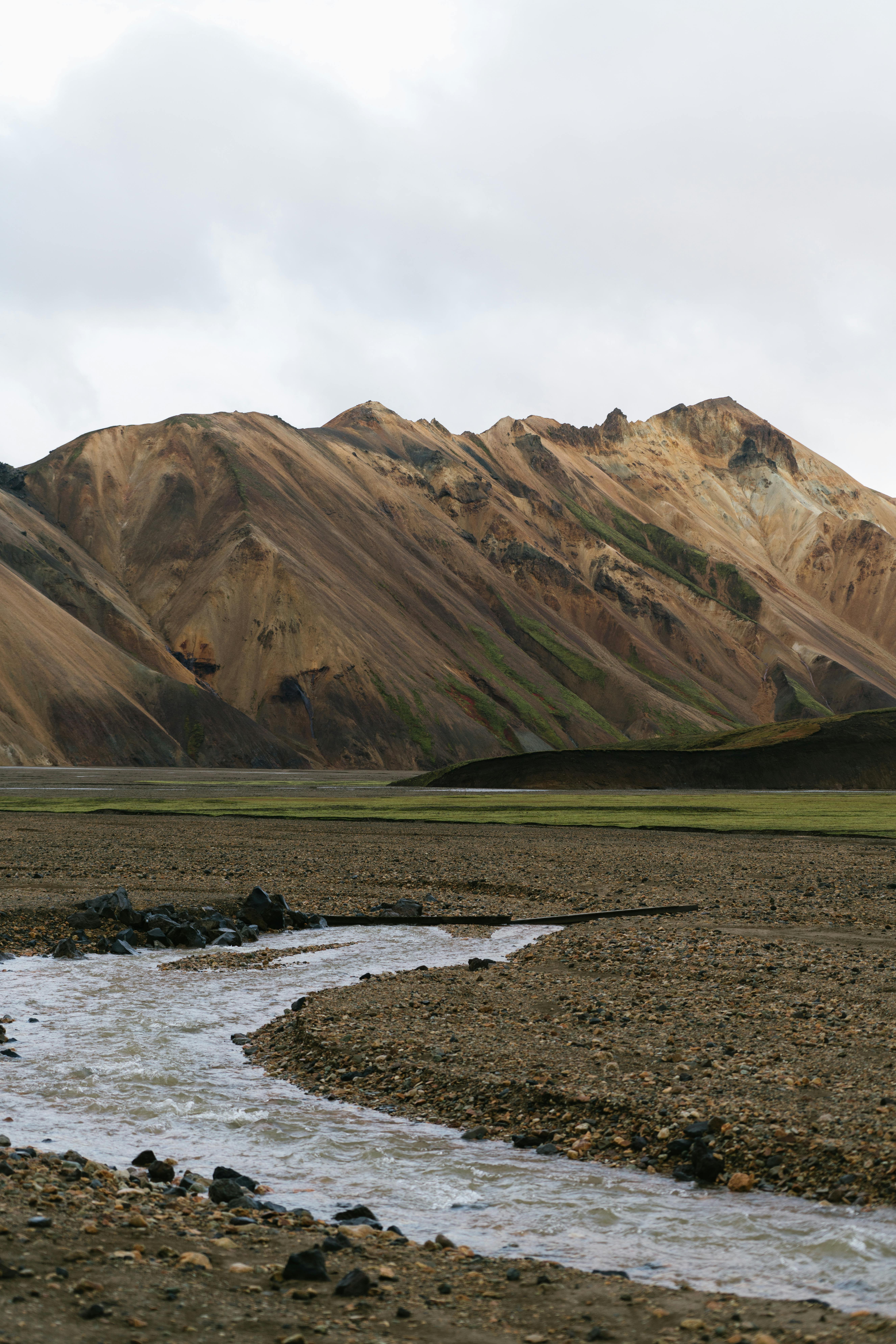 Shallow river passing near sandy ridge under serene sky · Free Stock Photo