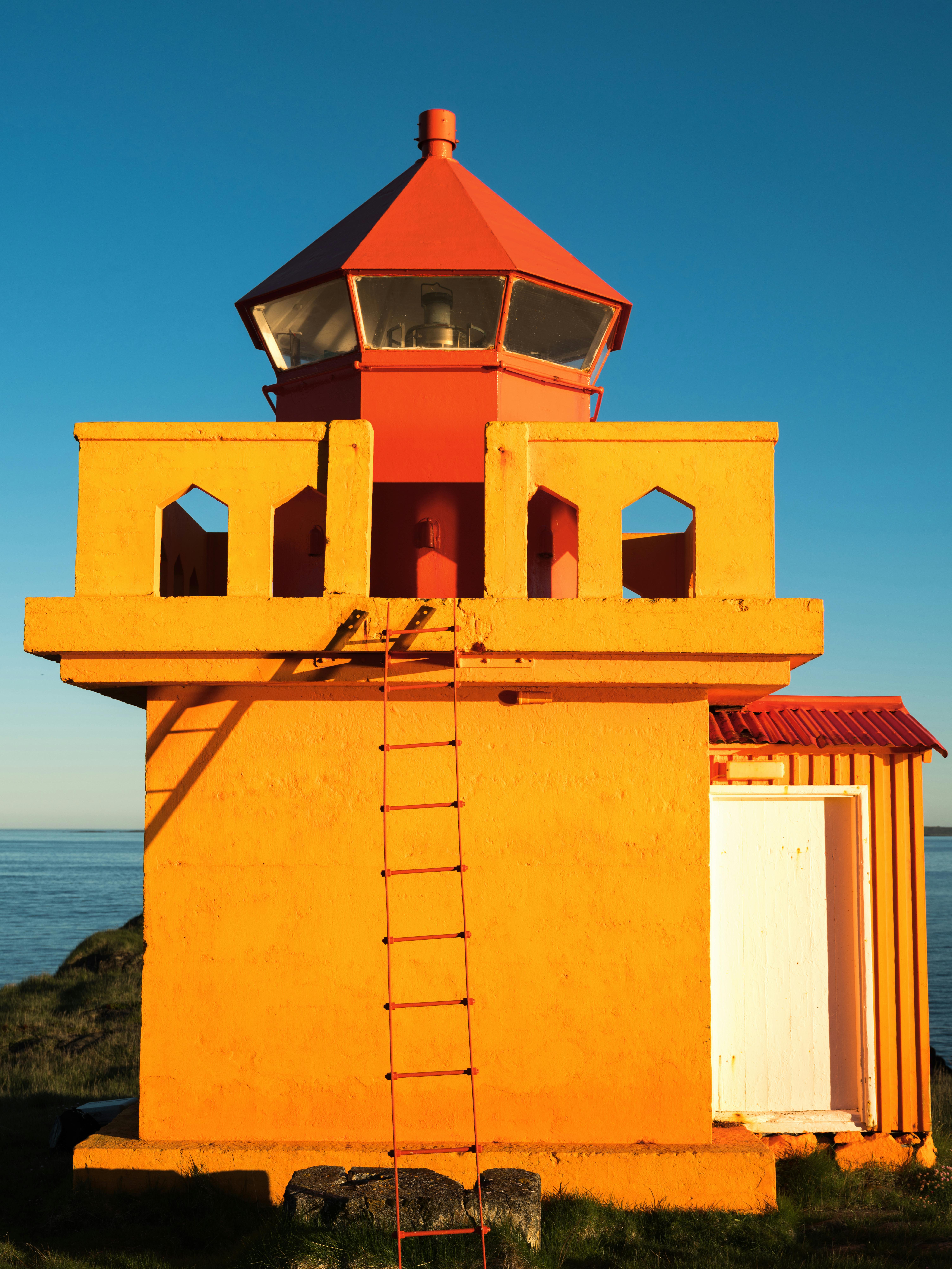 Colorful small beacon on seashore on clear day · Free Stock Photo