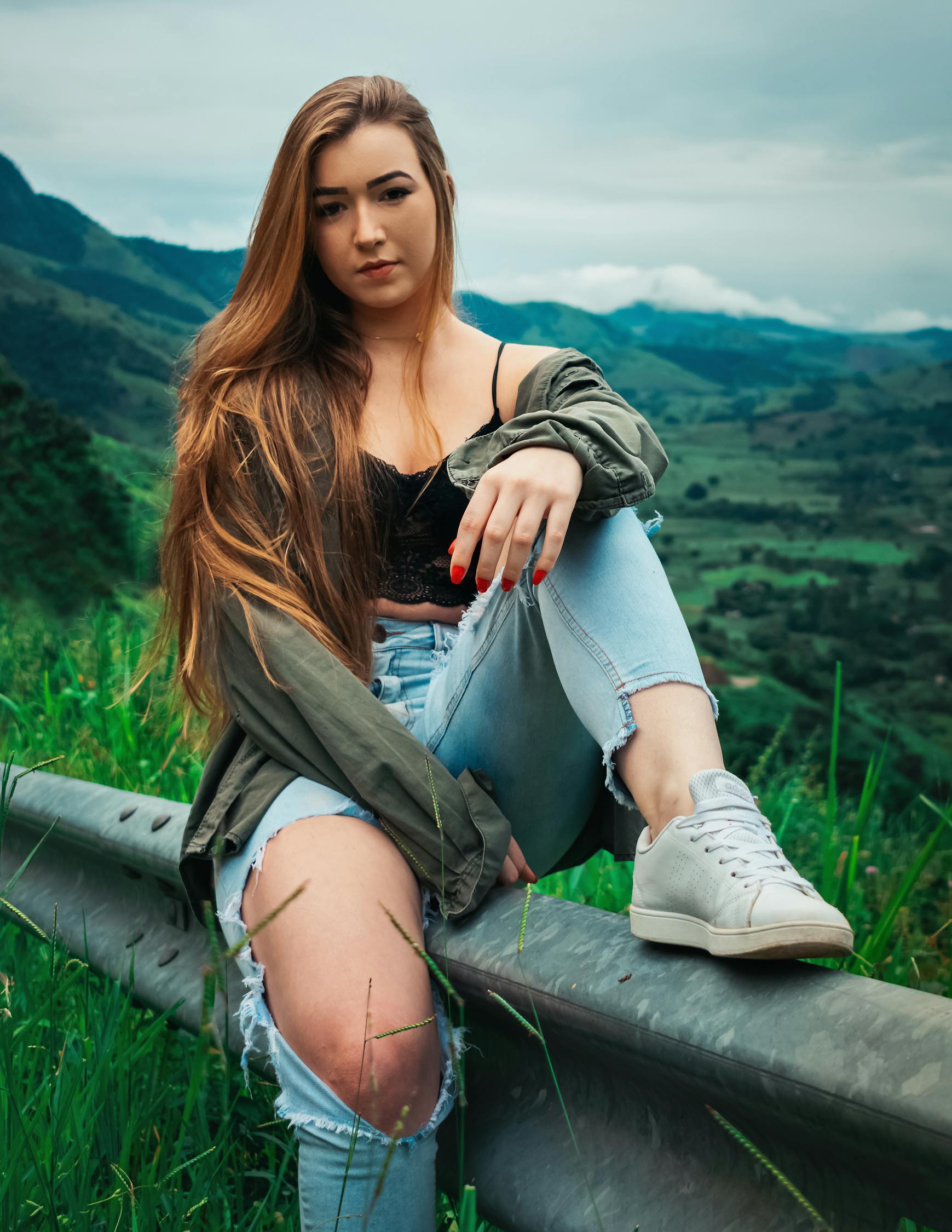 Woman In Gray Jacket And Blue Denim Jeans Sitting On Green Grass Field