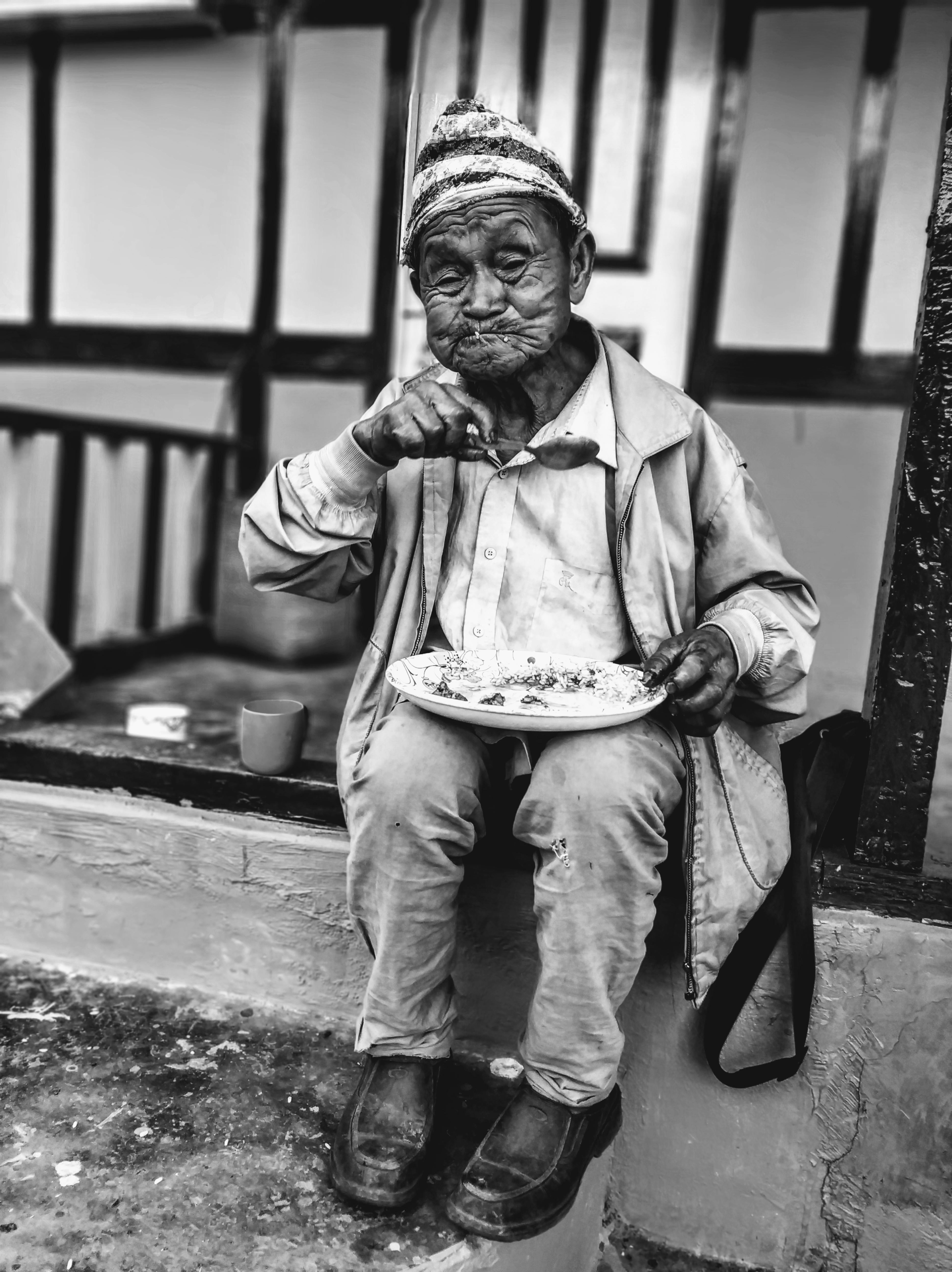 Aged ethnic poor man eating on street · Free Stock Photo