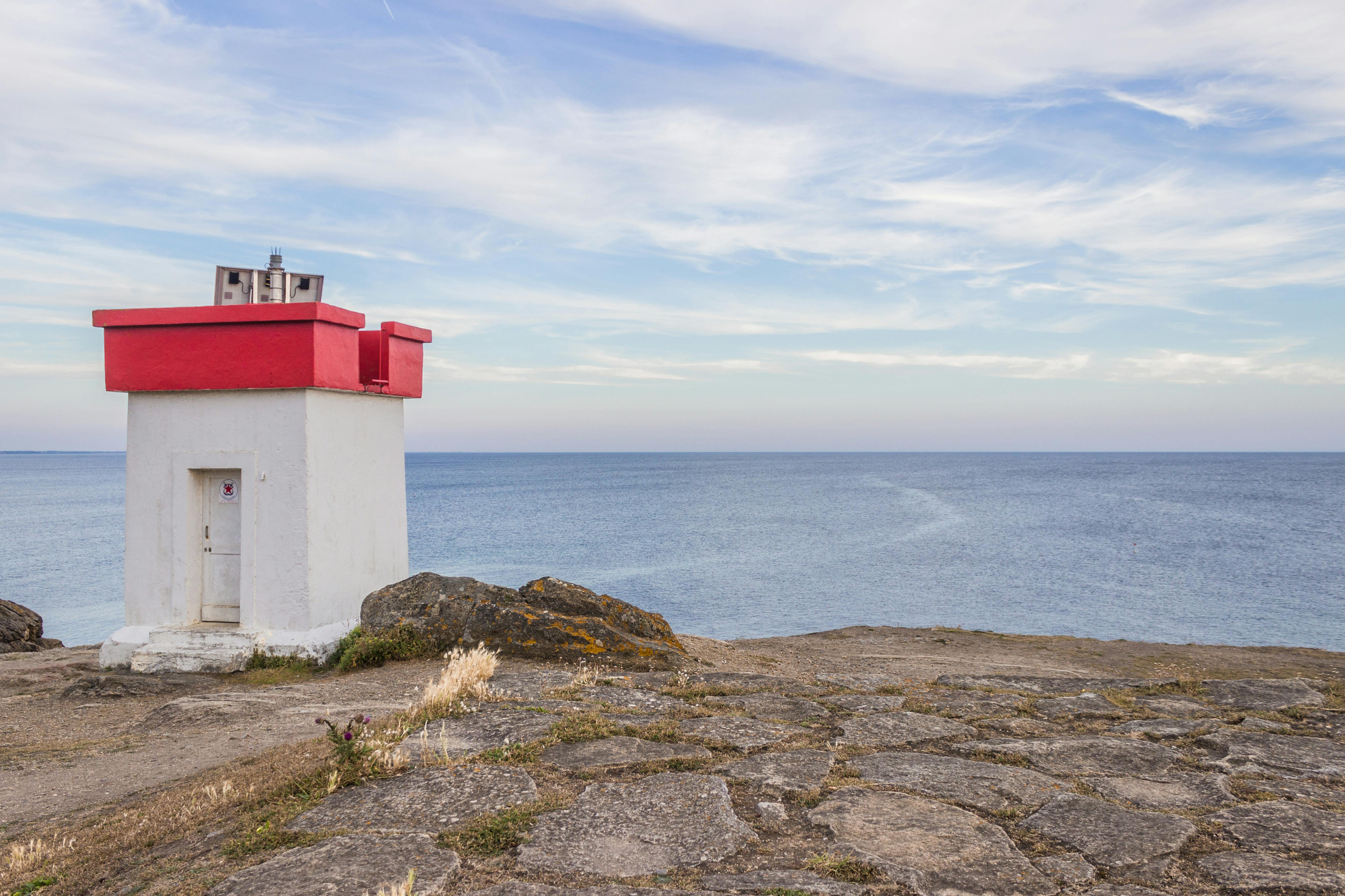 Old bright lighthouse on sandy shore in daytime · Free Stock Photo