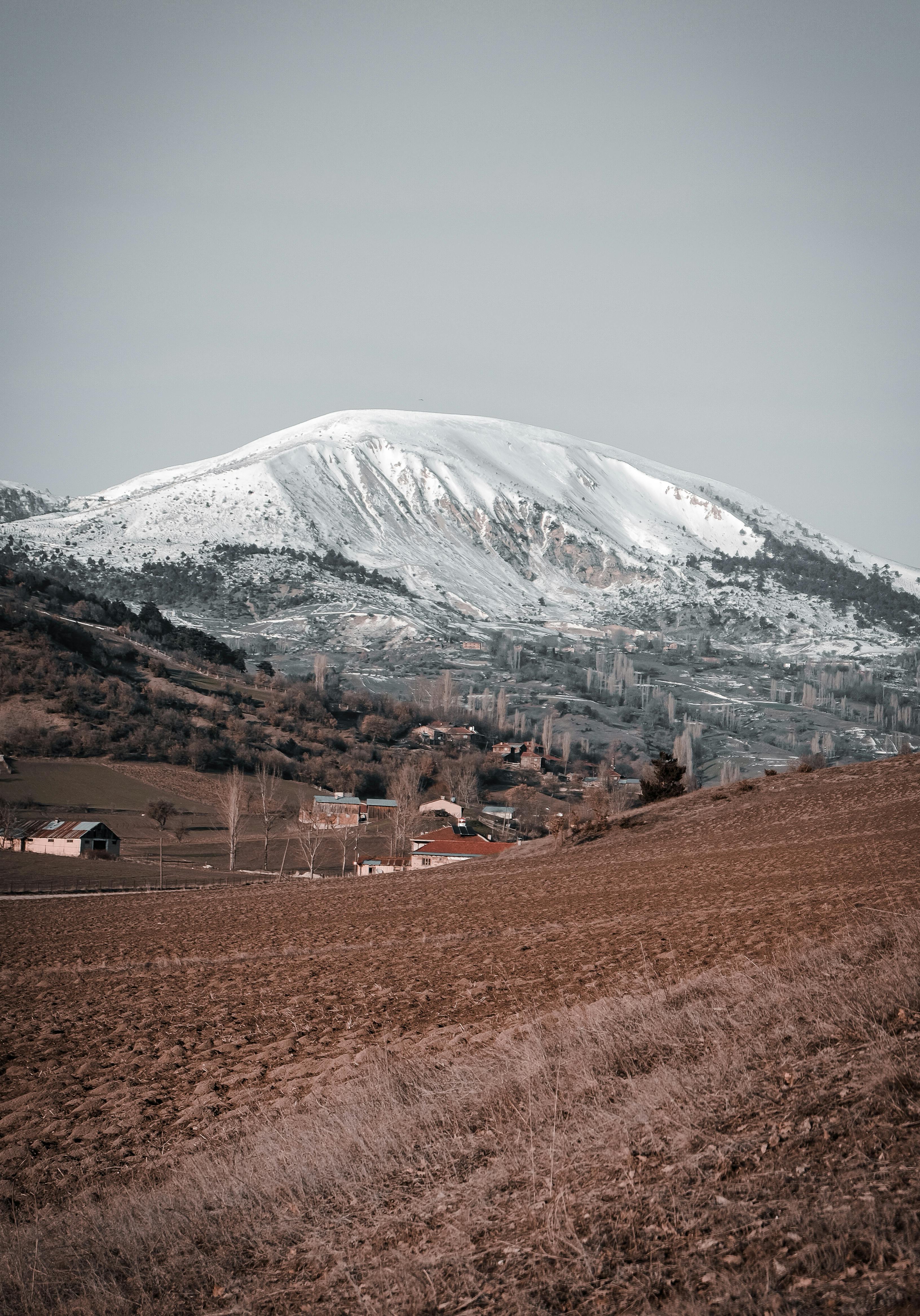Snowy mountain near dry terrain under sky · Free Stock Photo