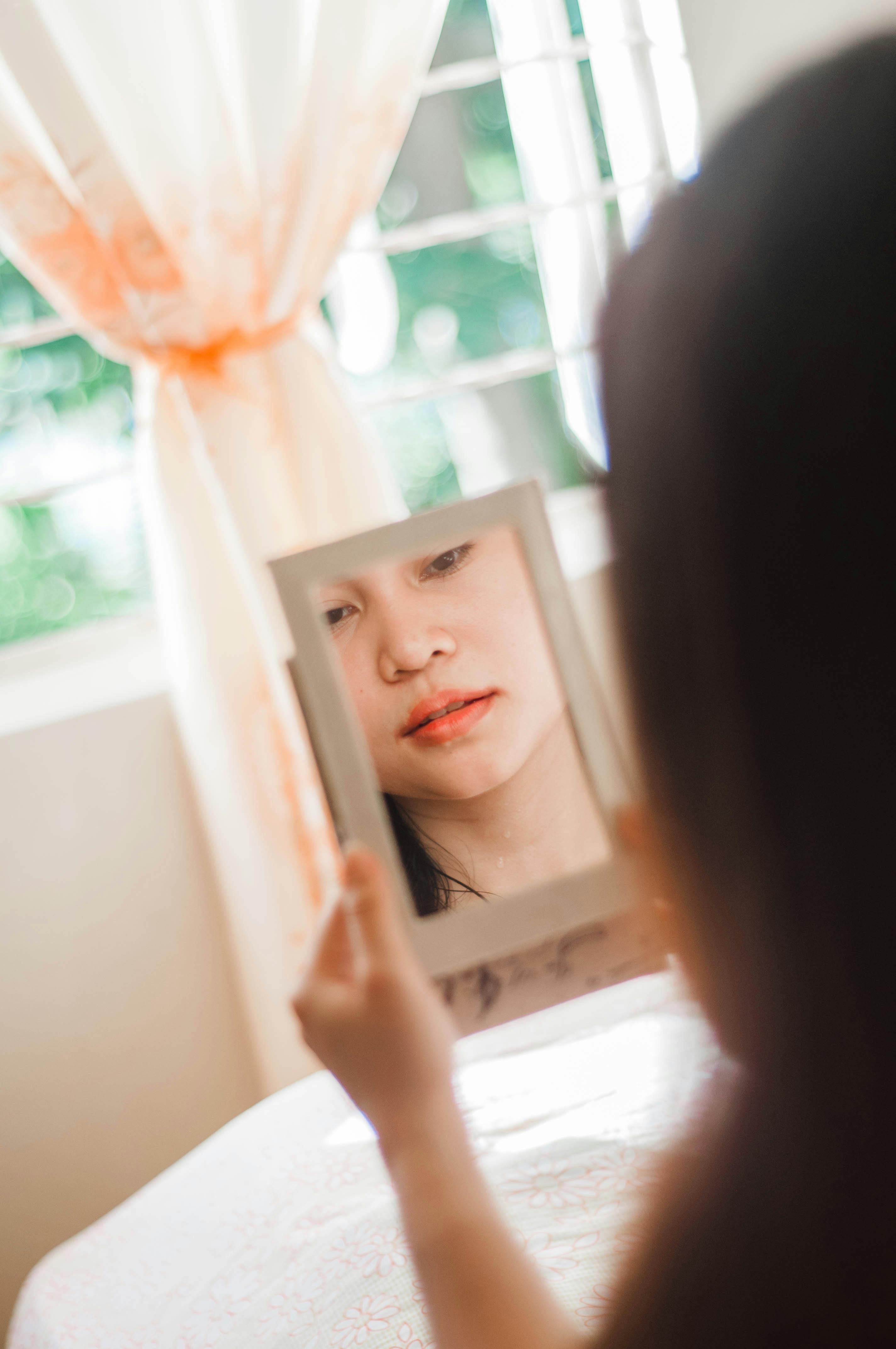 Woman reflecting in mirror while applying makeup · Free Stock Photo