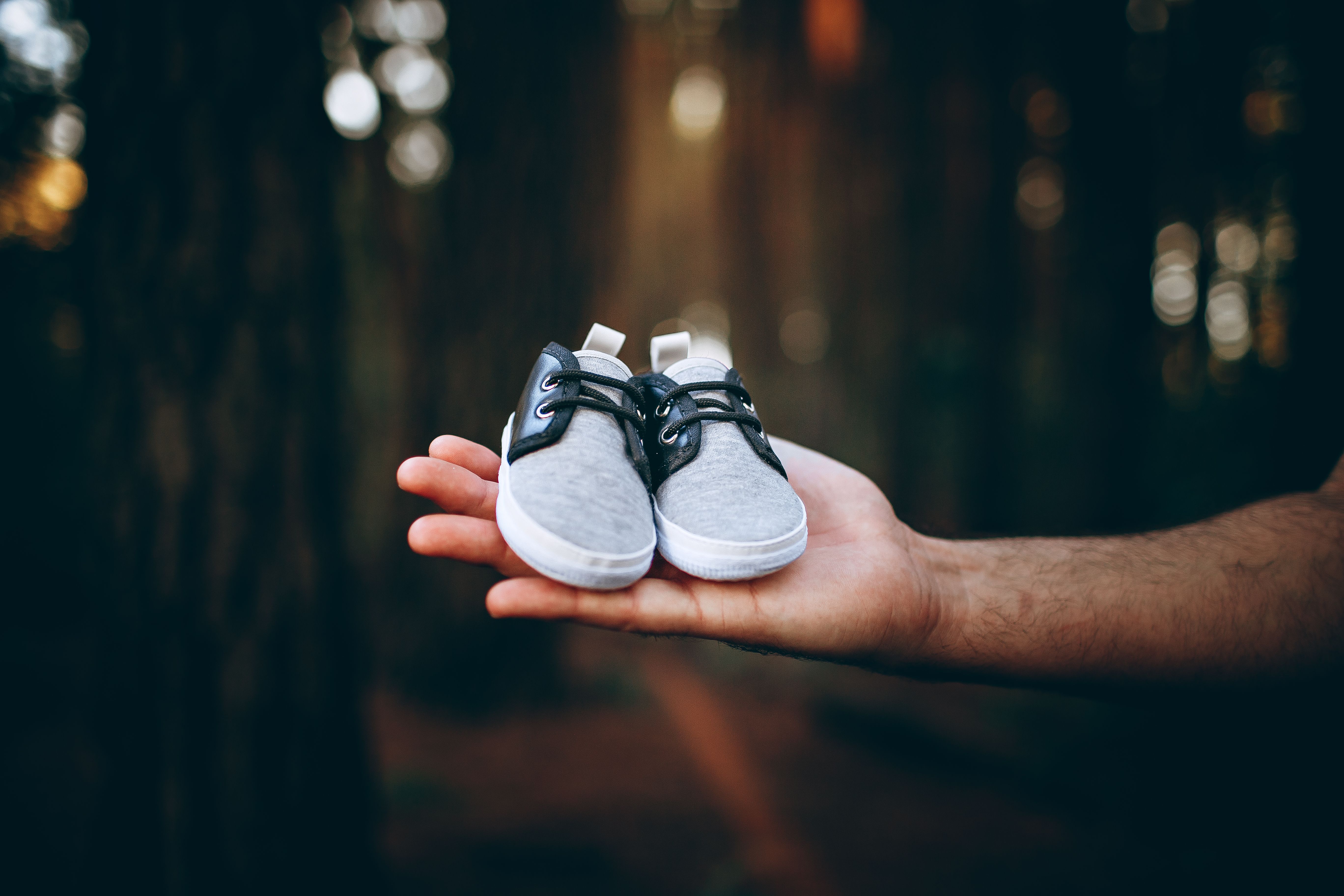 Tiny sneakers on hand of man in nature · Free Stock Photo