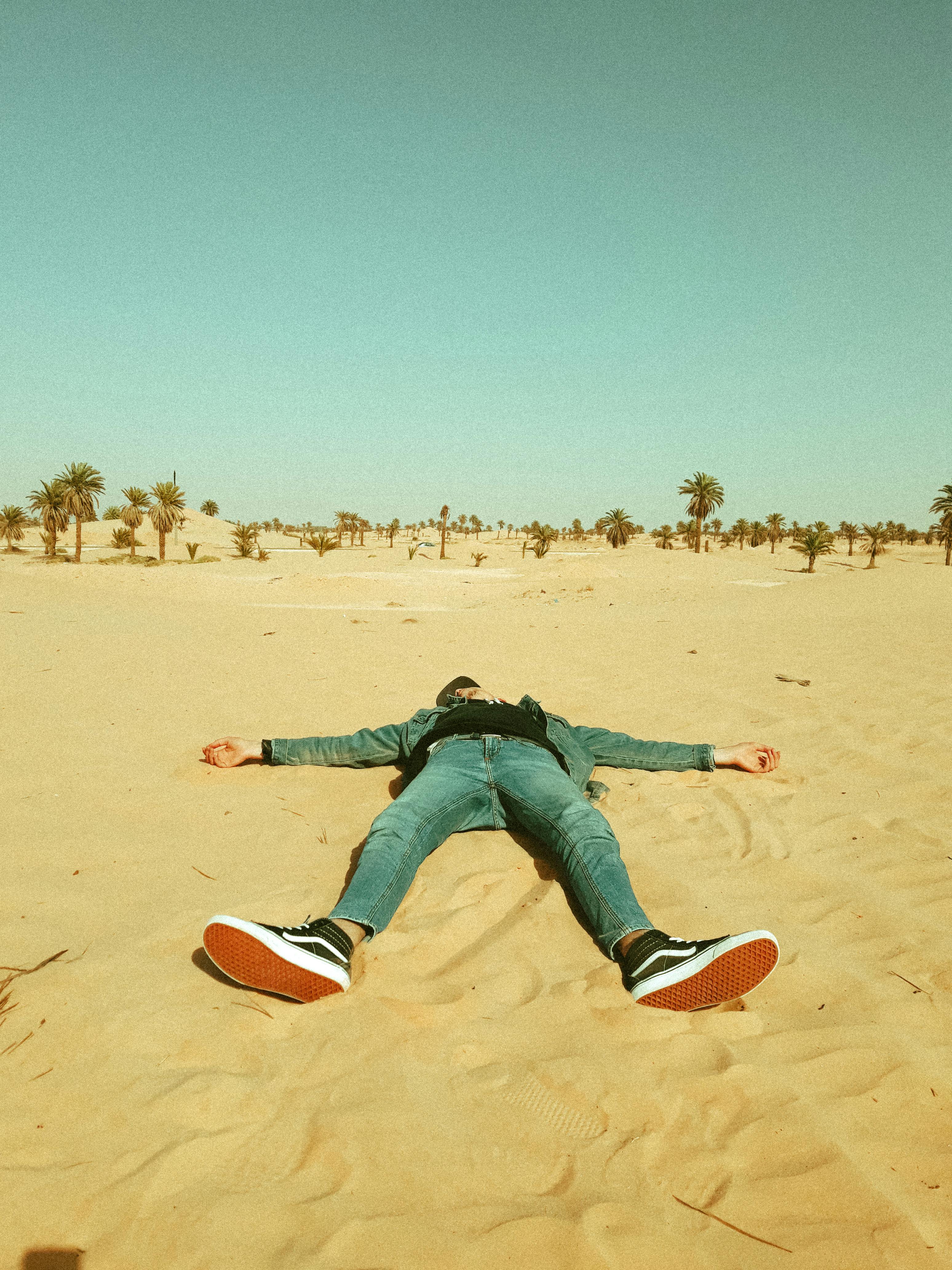 Man in Blue Denim Jacket and Jeans Lying Down on Desert Sand · Free ...