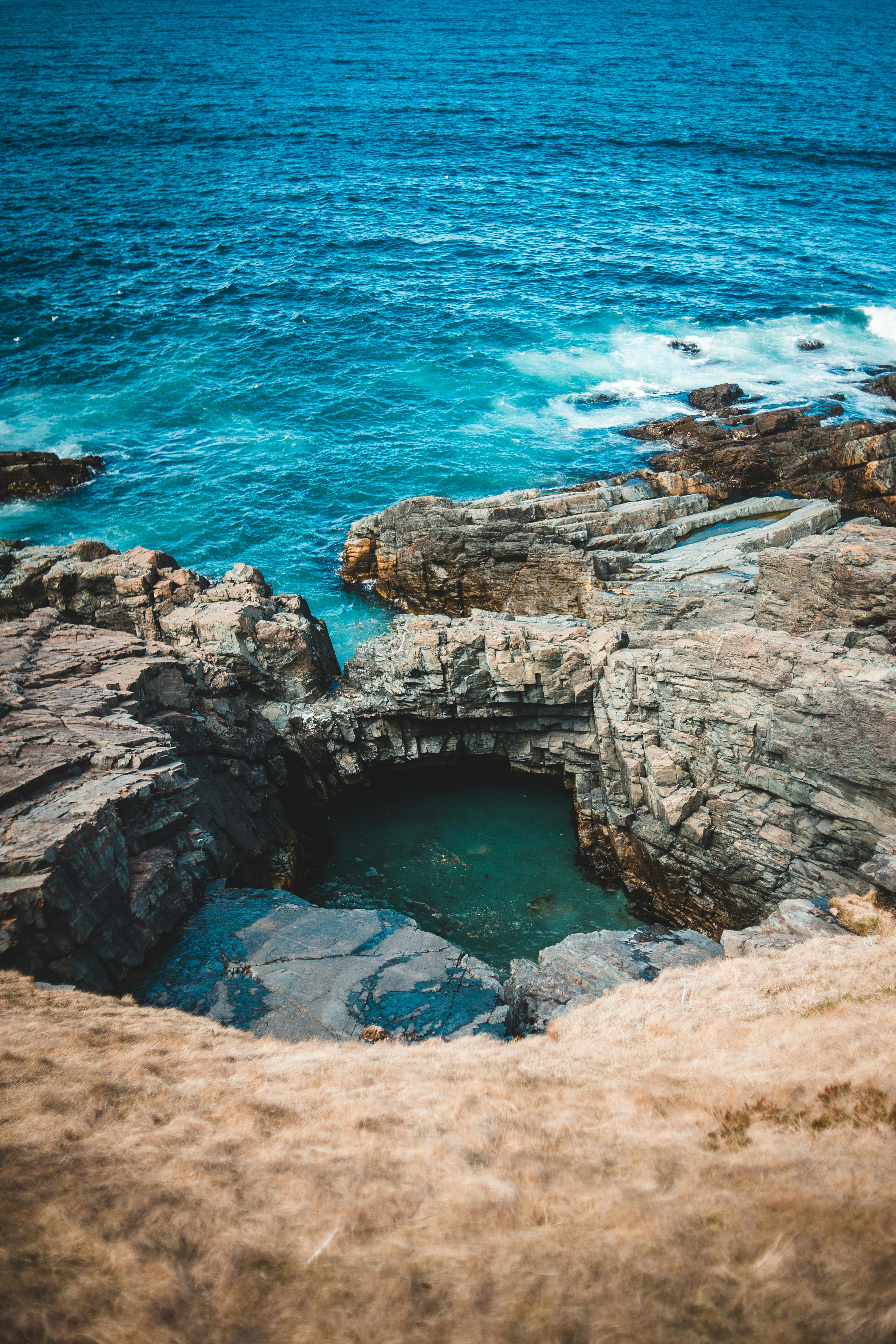 Rocky cliff forming small bay with blue seawater · Free Stock Photo
