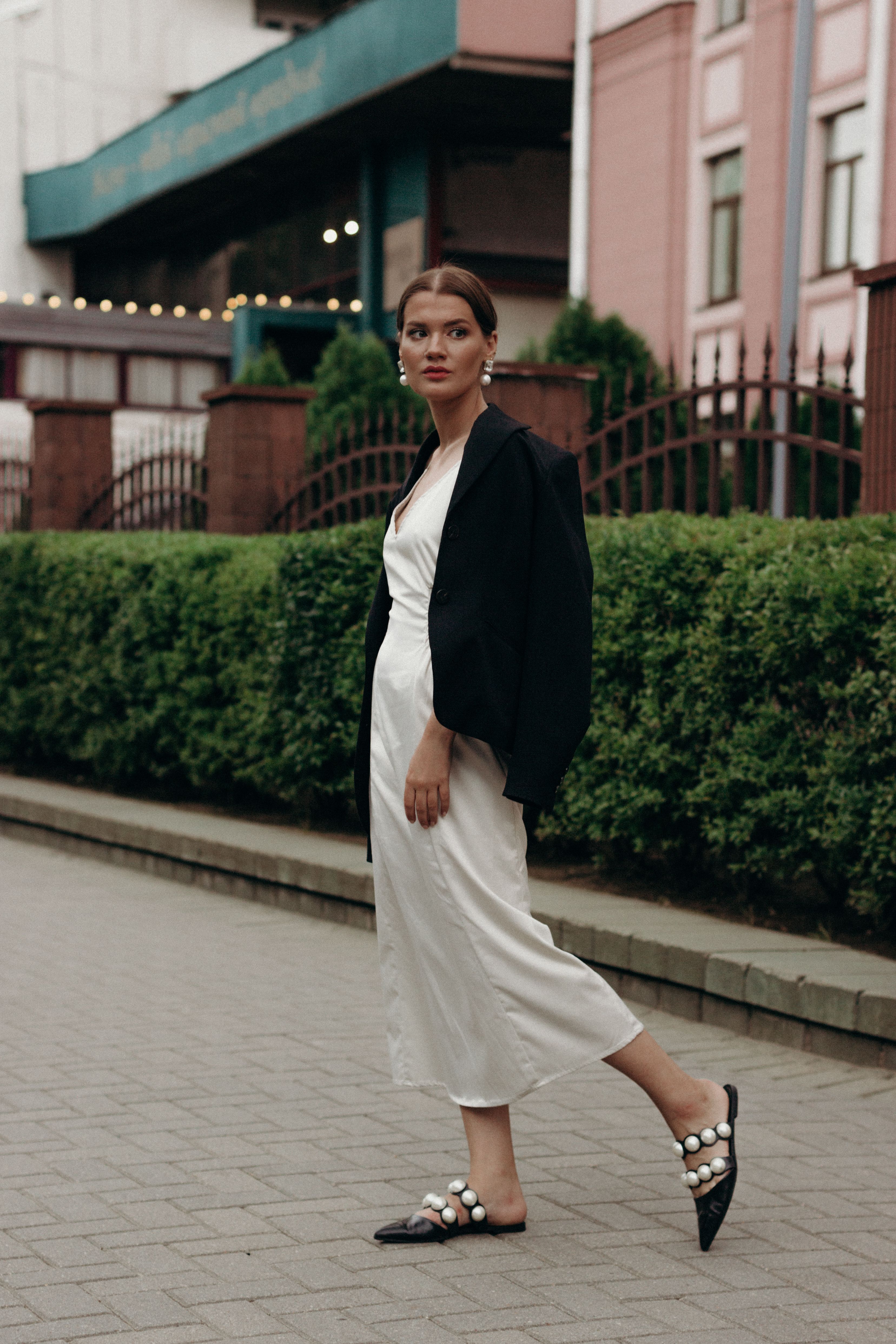 A Woman in White Dress Standing Draping Black Jacket Over Shoulders ...