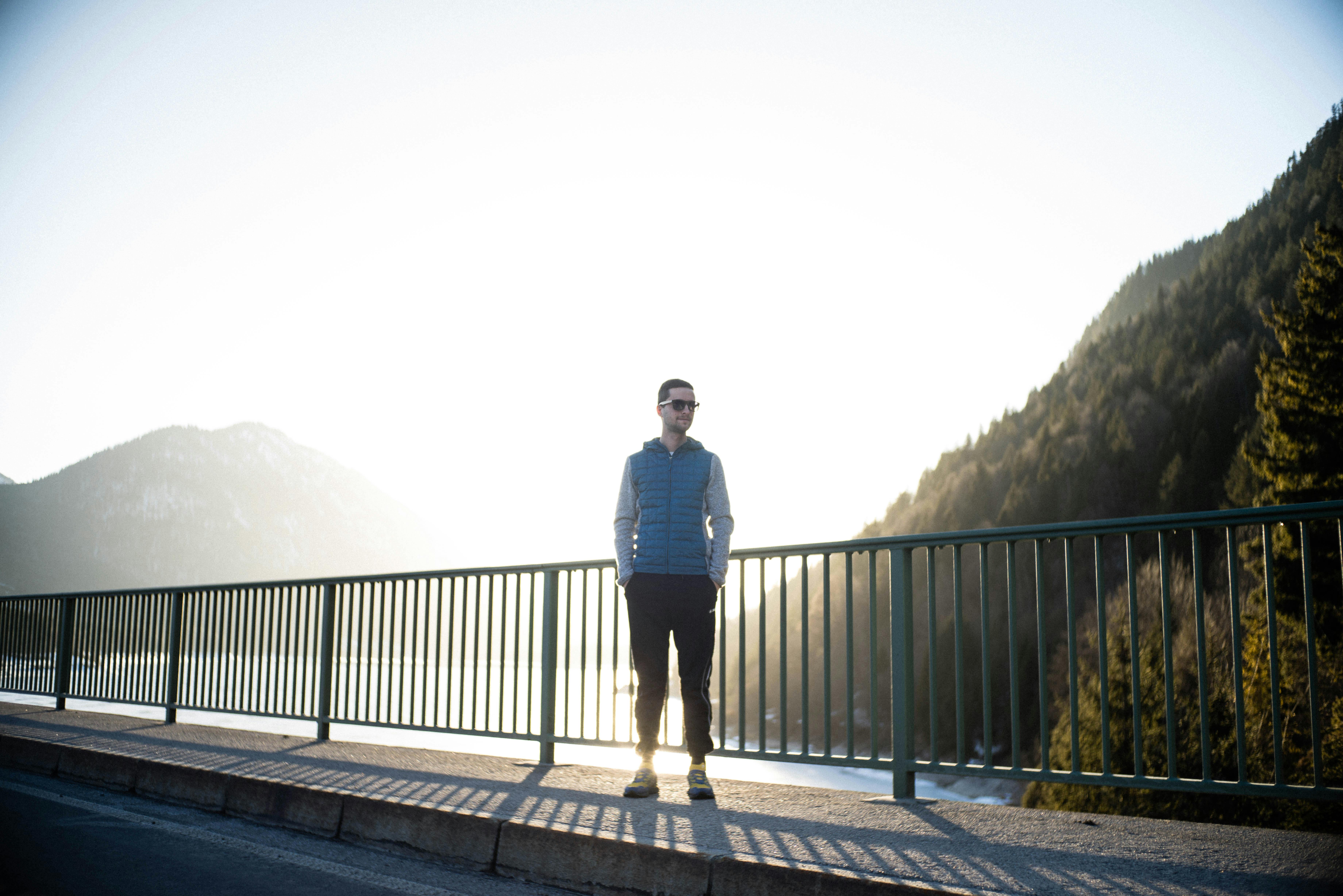 Man Standing on Road Beside Railings · Free Stock Photo