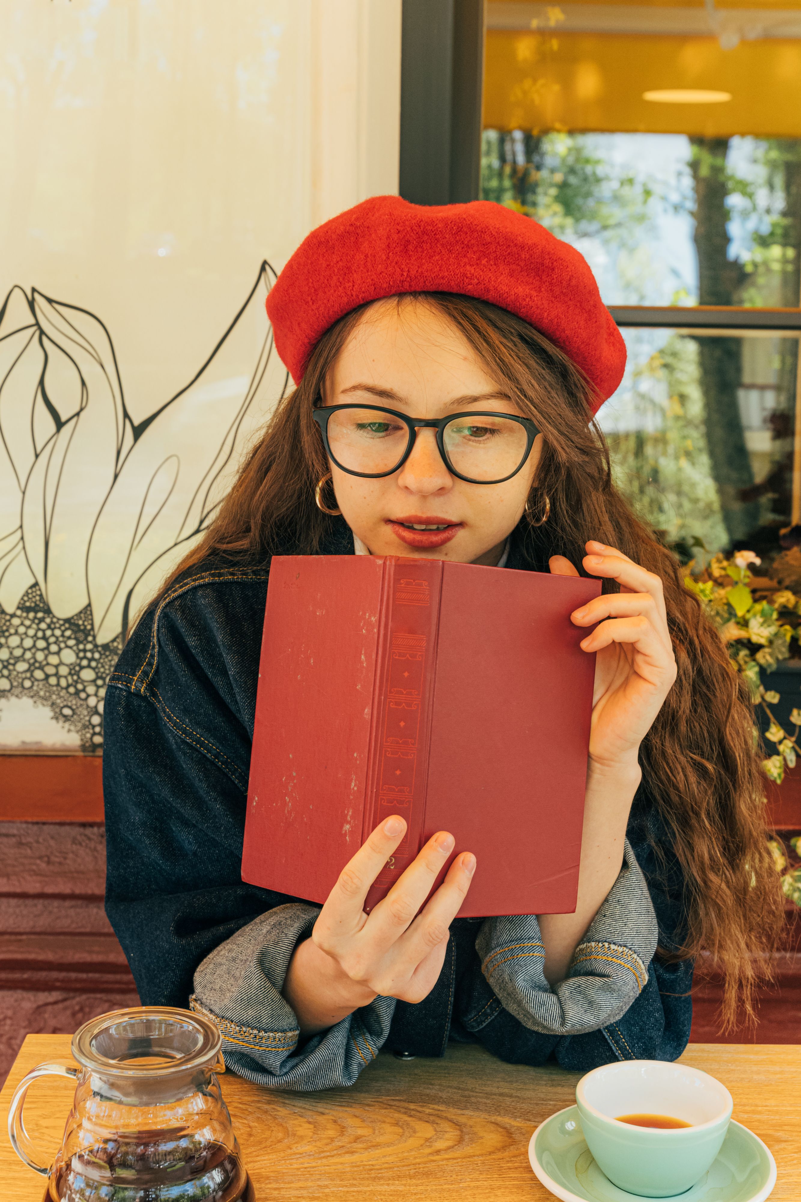 A Woman Reading a Book at a Coffee Shop · Free Stock Photo