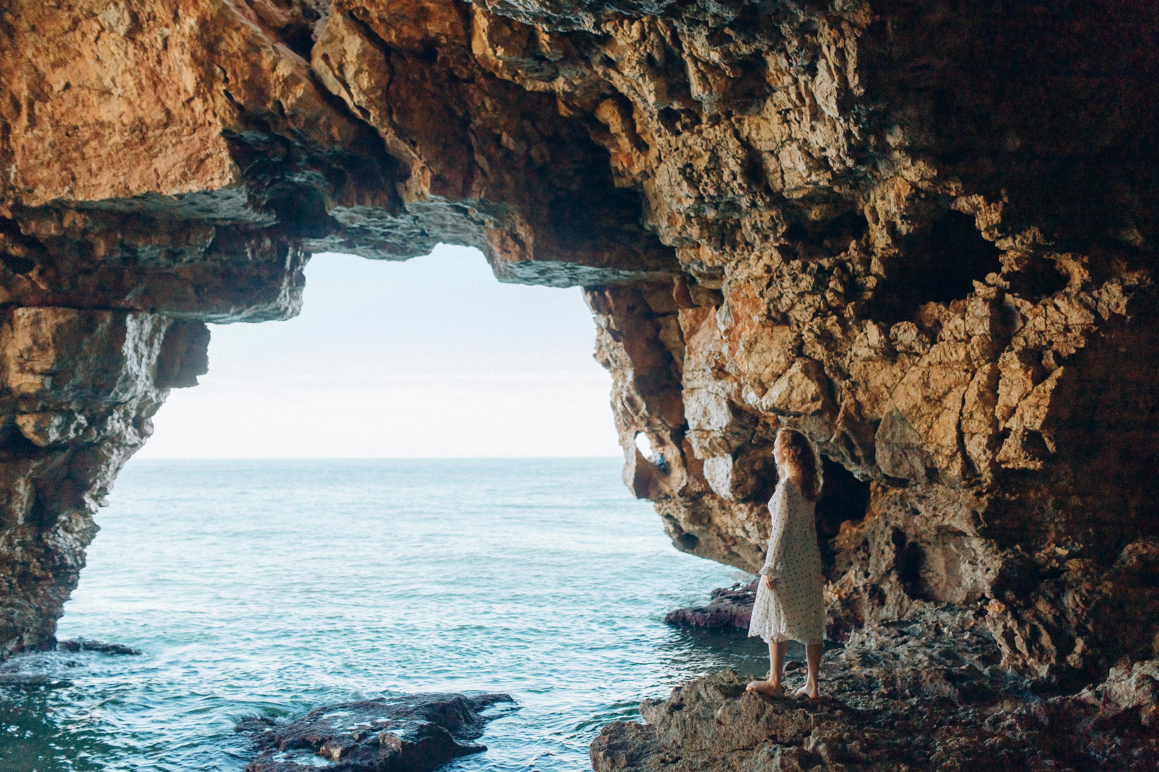 Silhouette of Person Standing Under the Rock Formation · Free Stock Photo