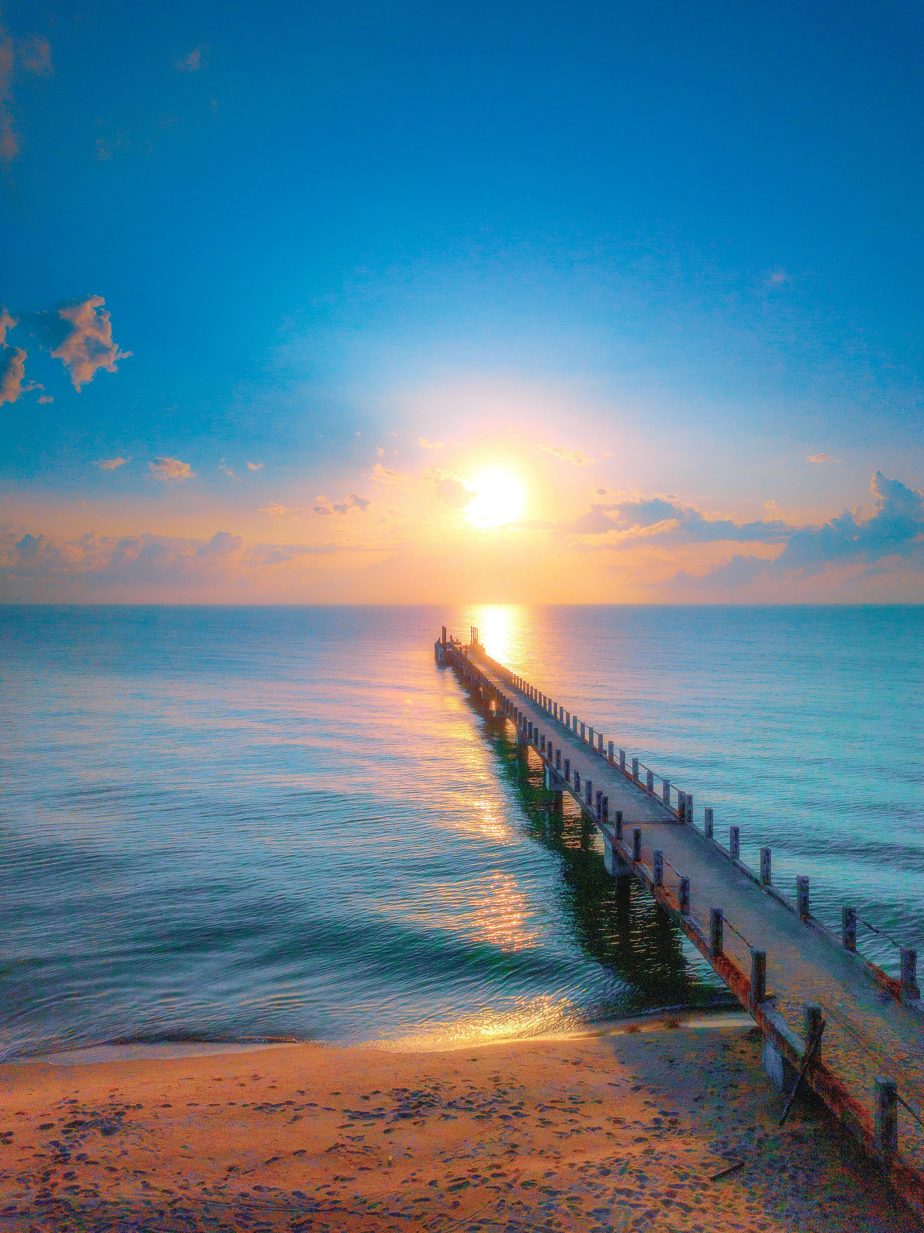 Vibrant sunset above long pier · Free Stock Photo