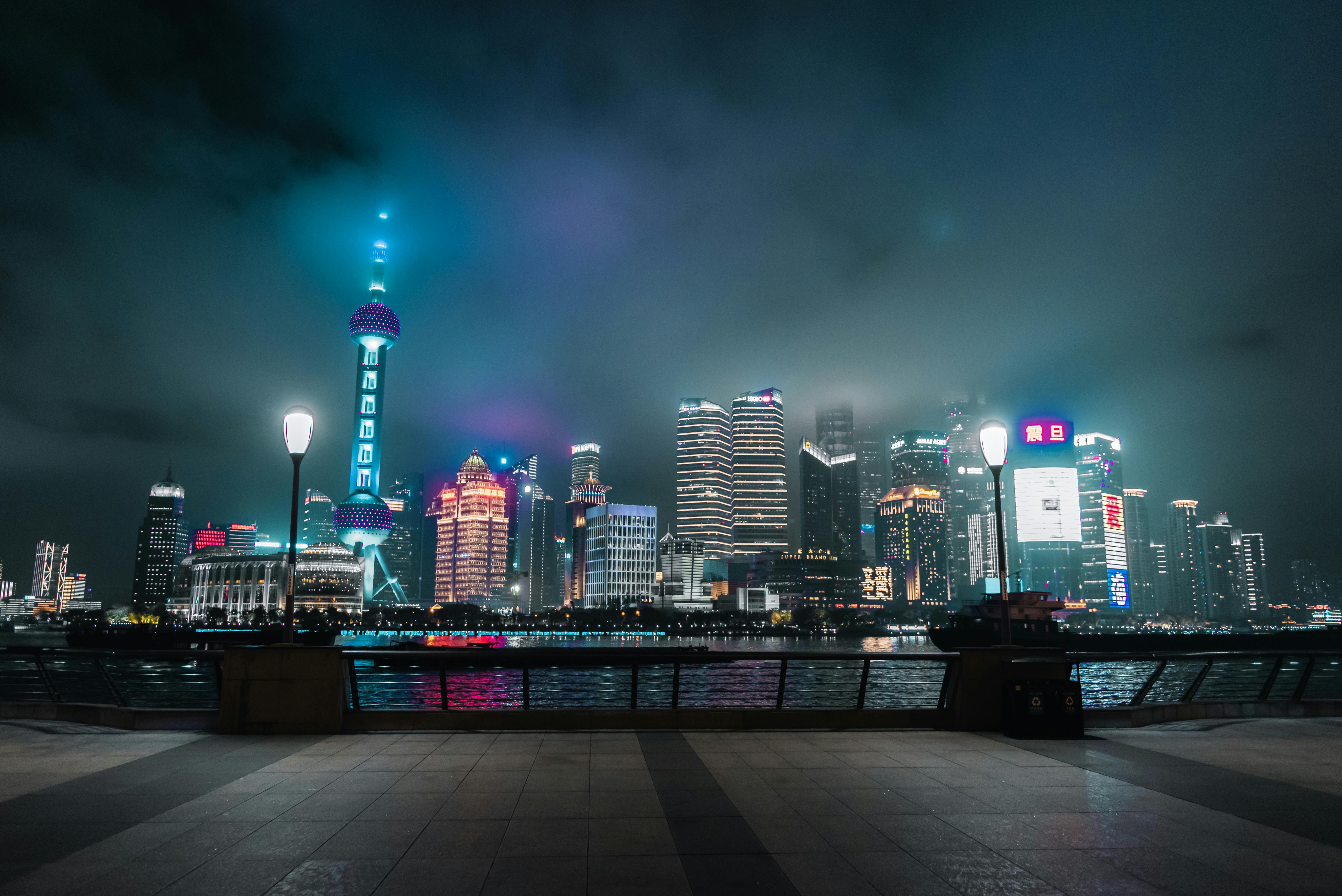 Modern skyscrapers illuminated by street lights under sky in evening ...