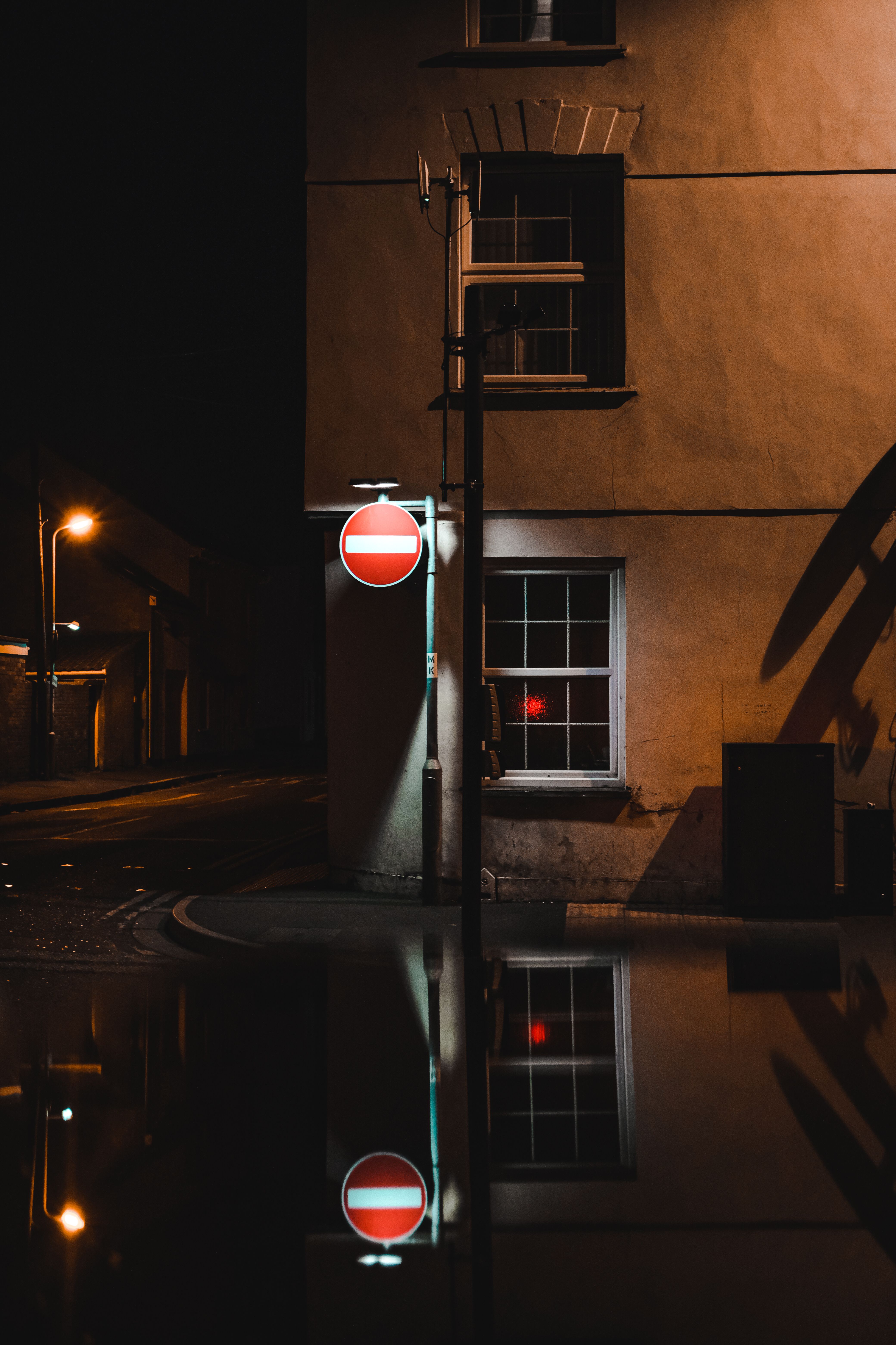 Old building with bright road sign reflecting in puddle · Free Stock Photo