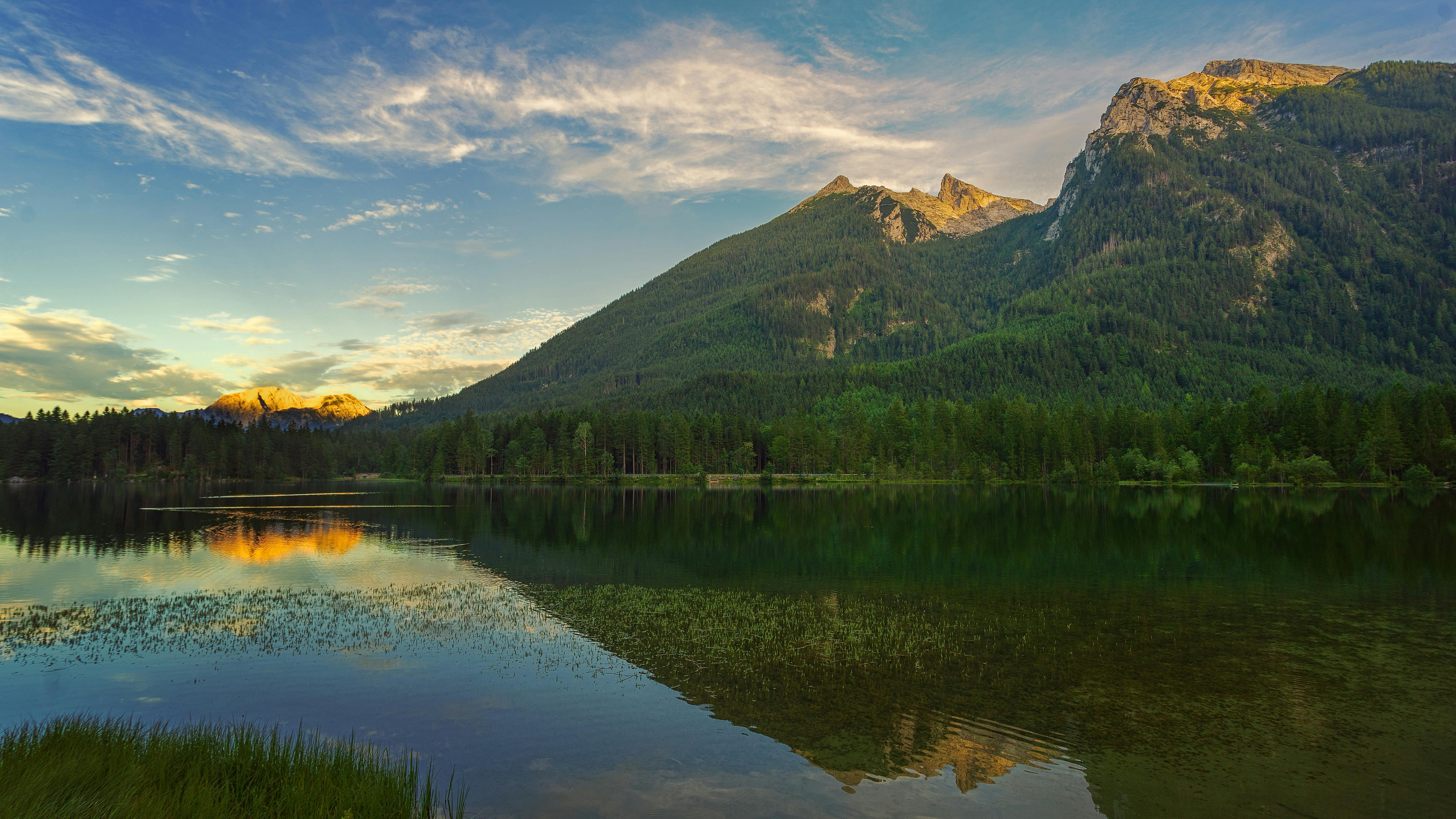 Lush green mountain range near calm lake · Free Stock Photo