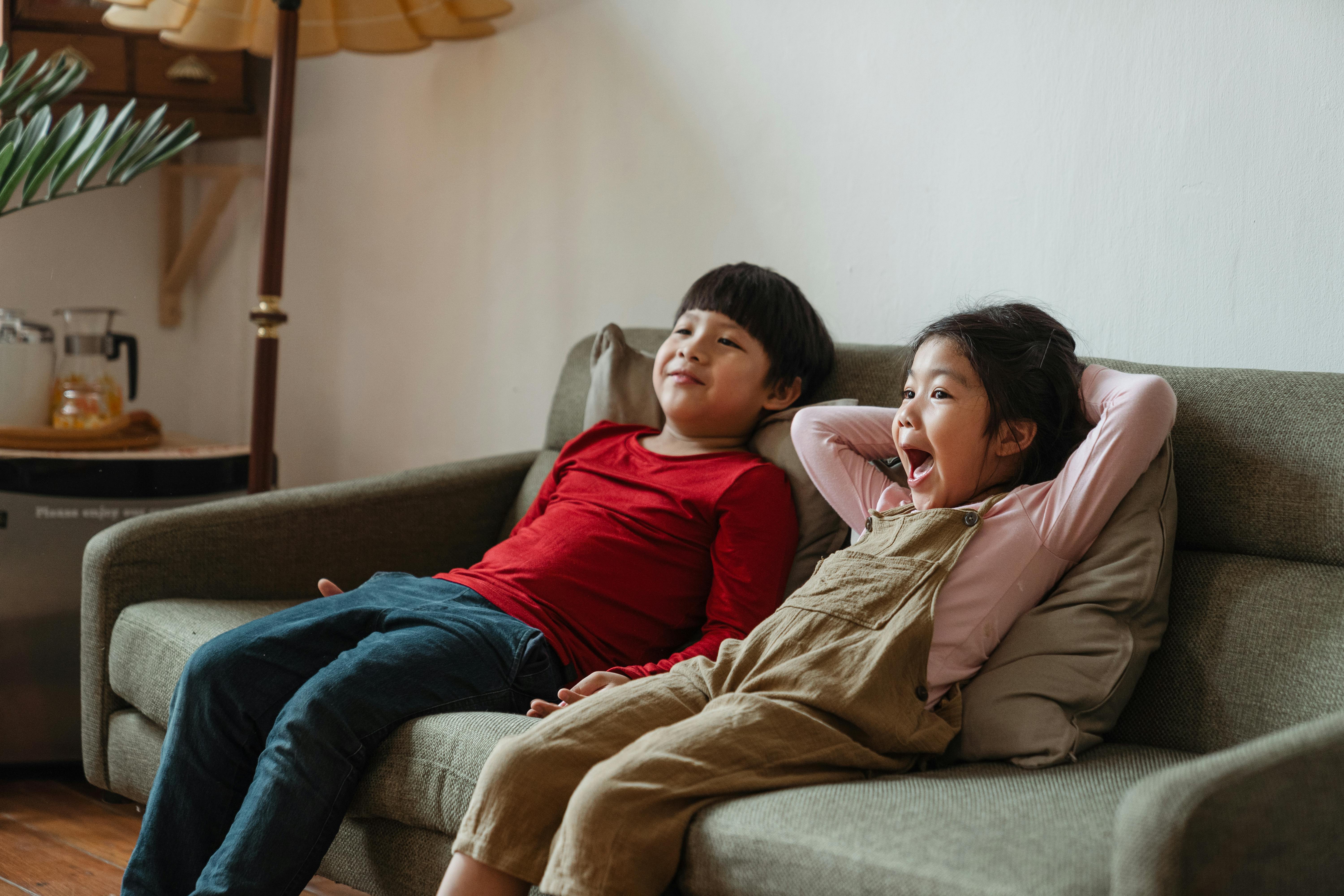 Photo of Two Kids Standing on Gray Sofa · Free Stock Photo