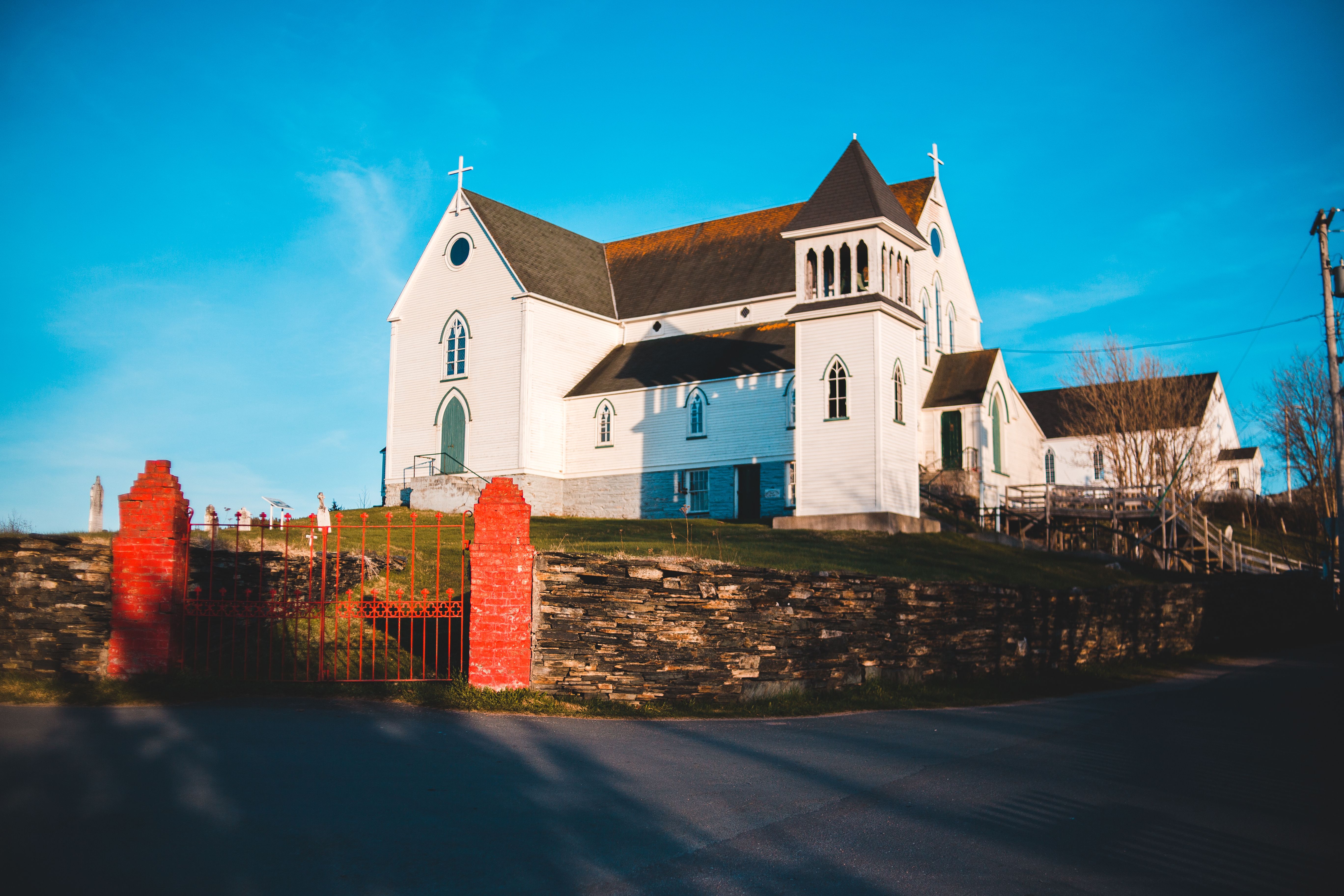 Aged church exterior on hillside under blue sky · Free Stock Photo