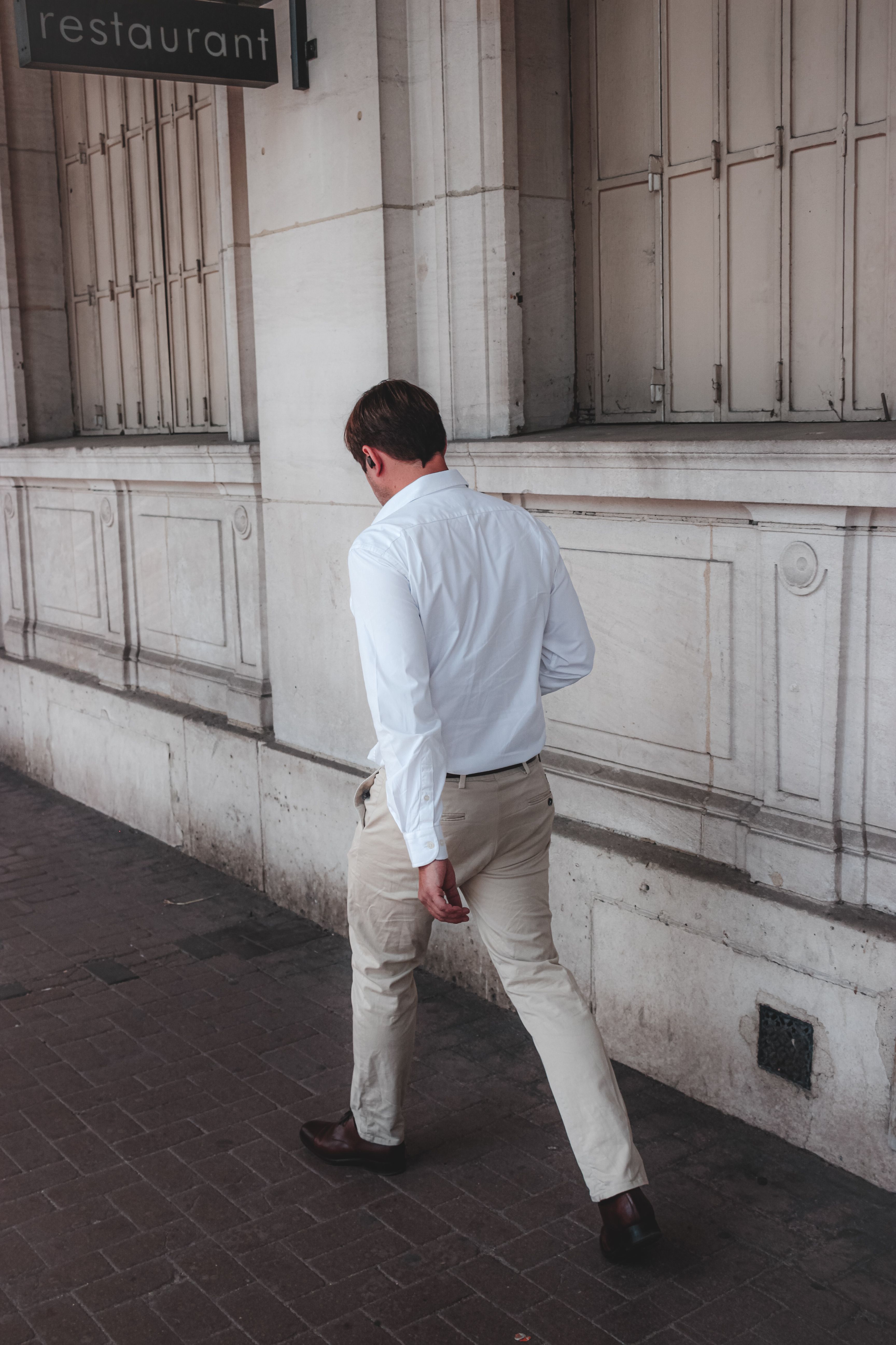 Unrecognizable man walking along white building wall · Free Stock Photo