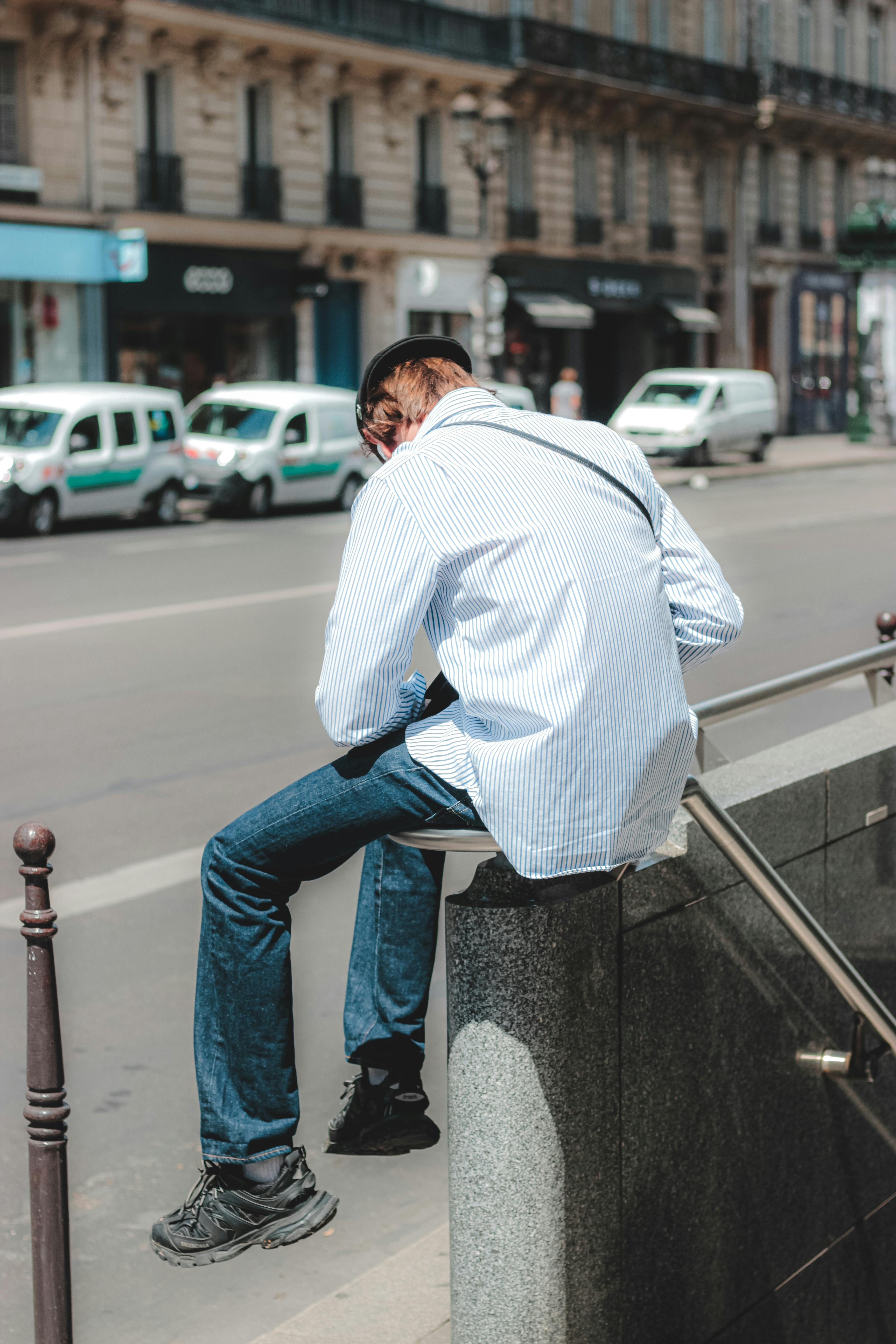 Faceless man sitting on street stone railing · Free Stock Photo