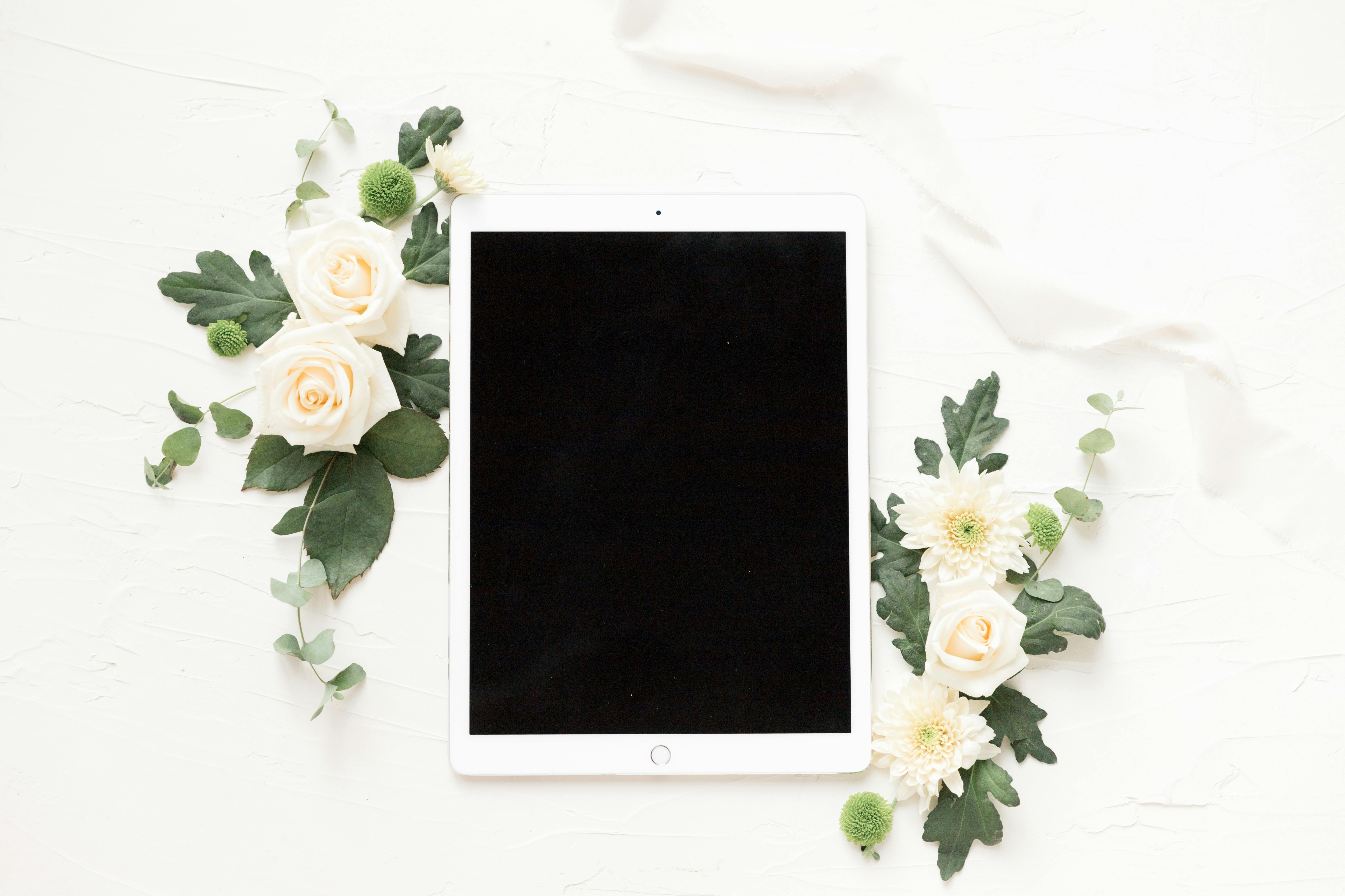 White Ipad on White Background Beside Blooming Flowers · Free Stock Photo