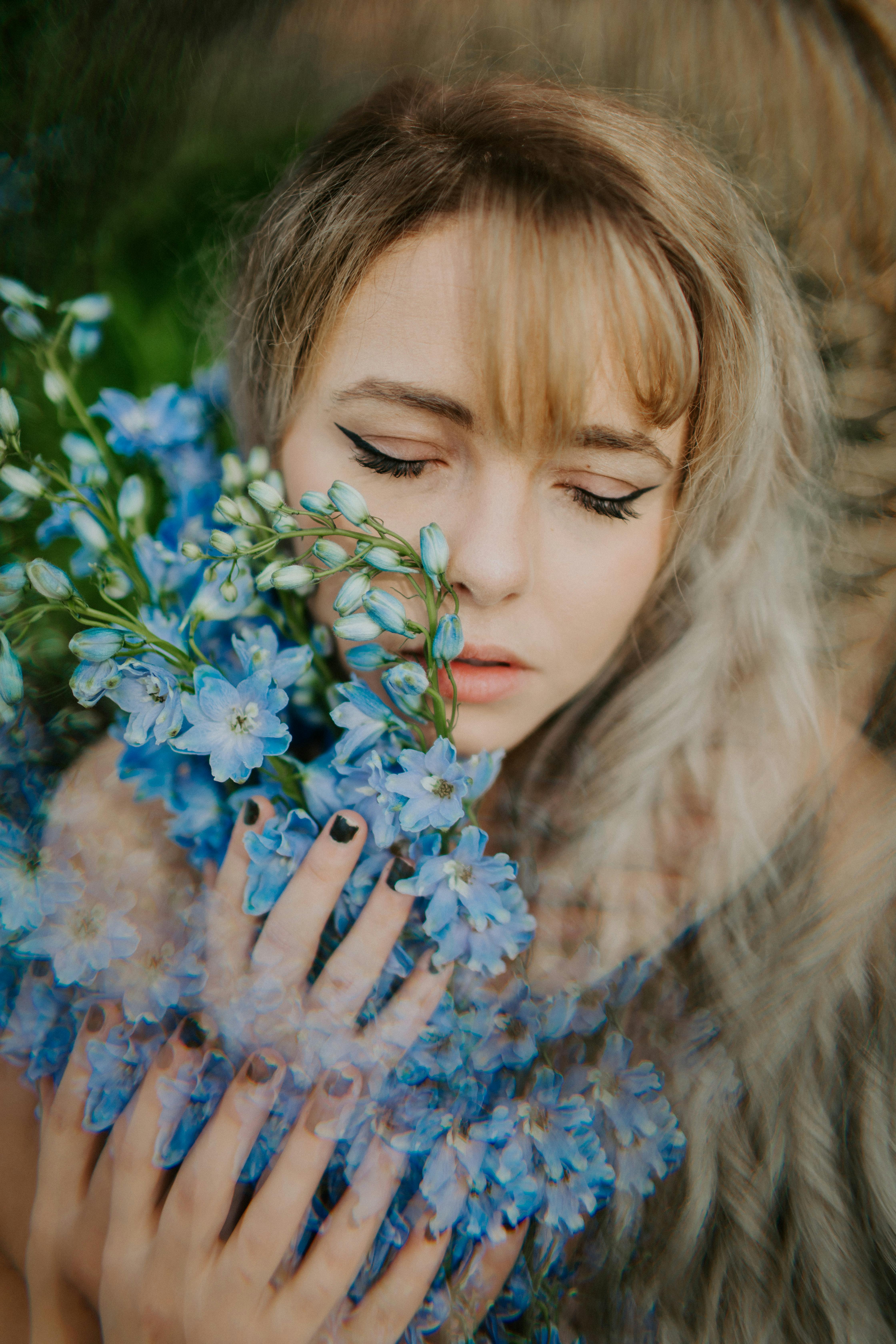 Portrait of a Blonde Woman Holding Blue Flowers · Free Stock Photo