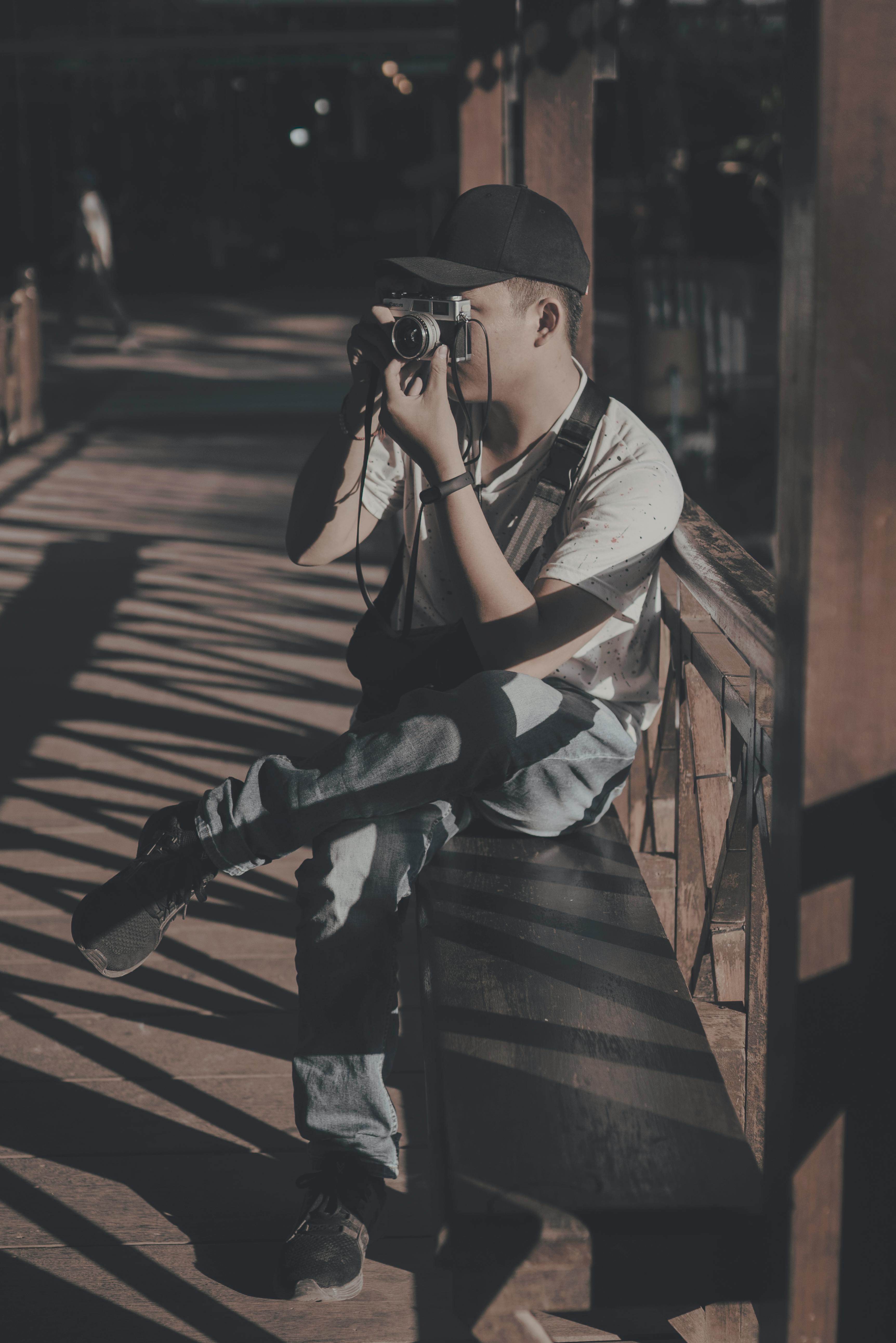 Photo of Man Sitting on Bench While Taking Photo Using Camera · Free ...