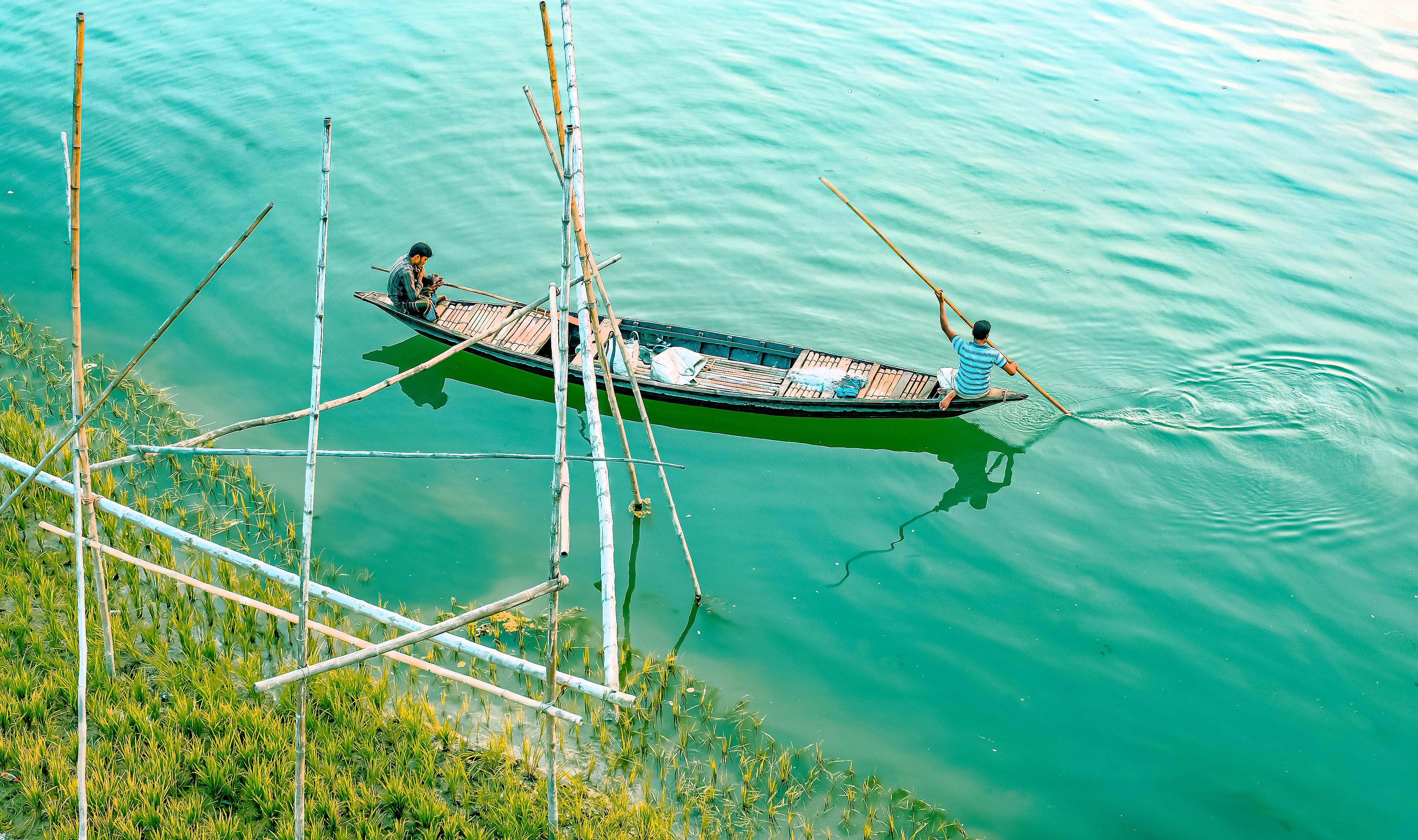 Ethnic men floating on canoe along pure blue lake · Free Stock Photo
