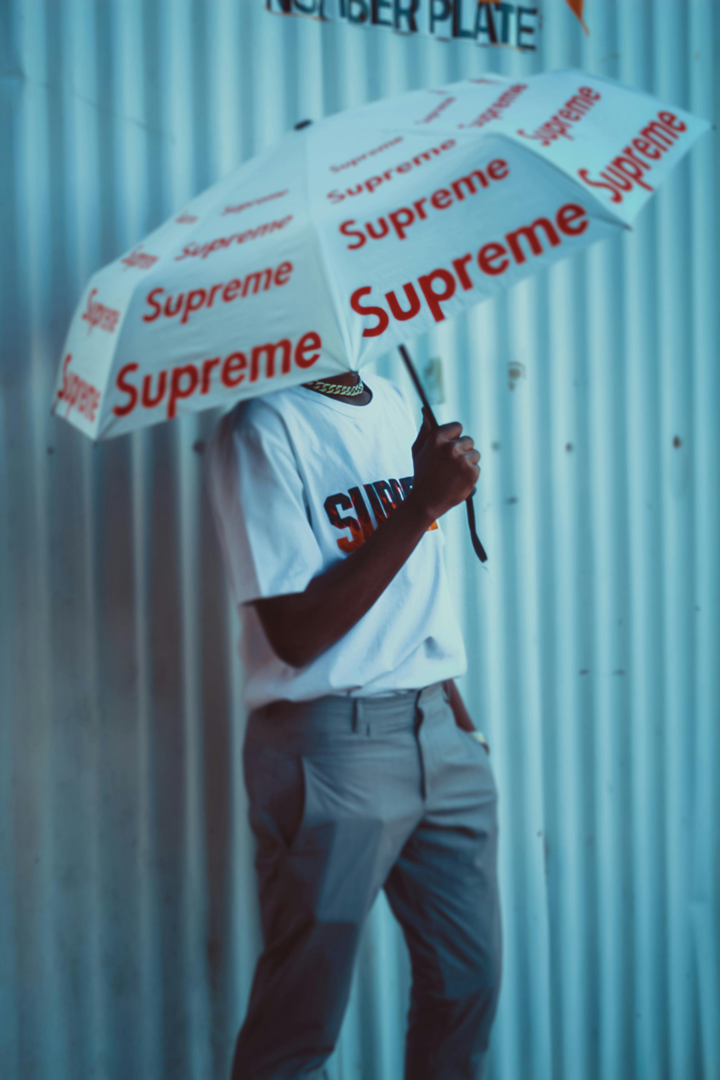 Anonymous black person with umbrella standing near metal wall · Free ...