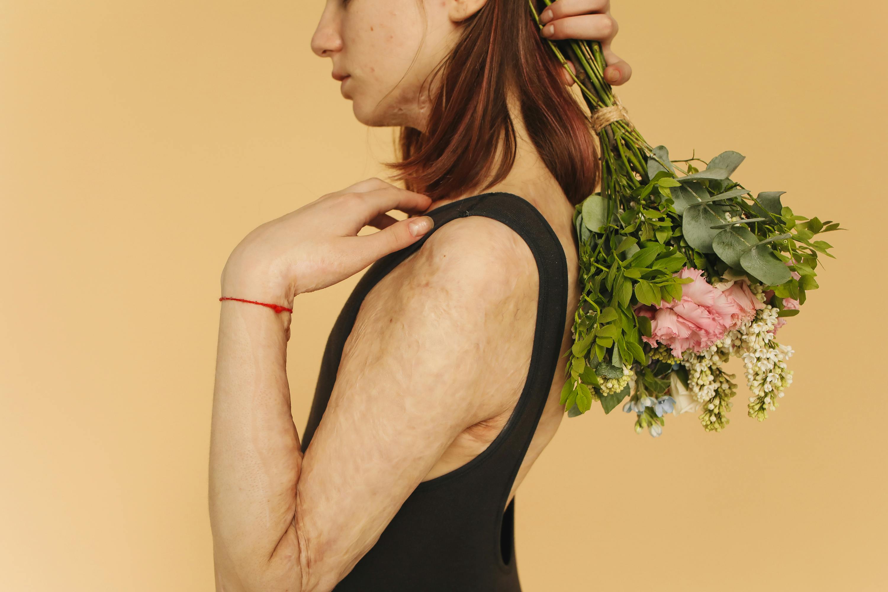 A Side View of a Woman in Black Tank Top Holding a Bouquet of Flowers ...