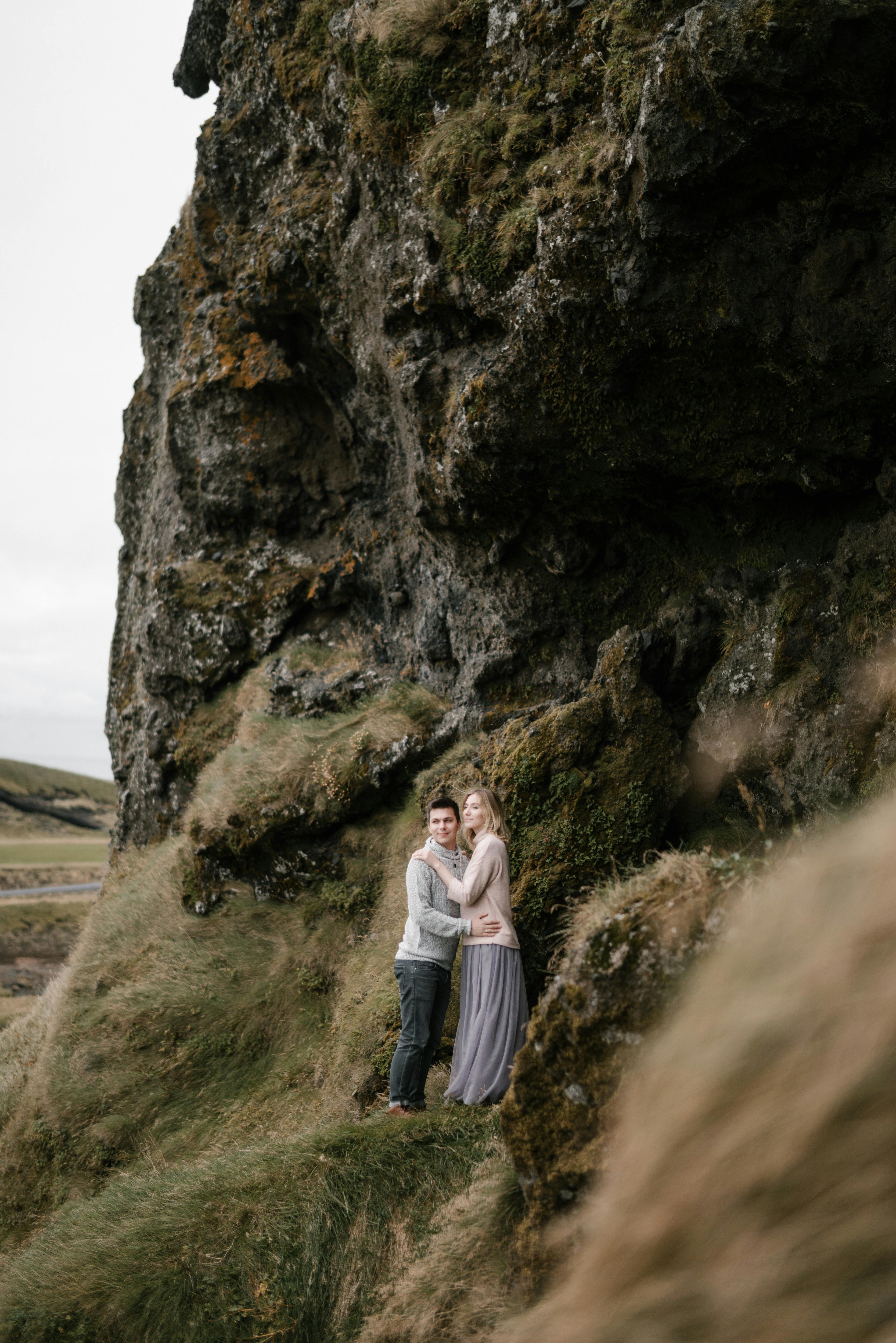 Young cuddling couple admiring landscape from rocky cliff · Free Stock ...