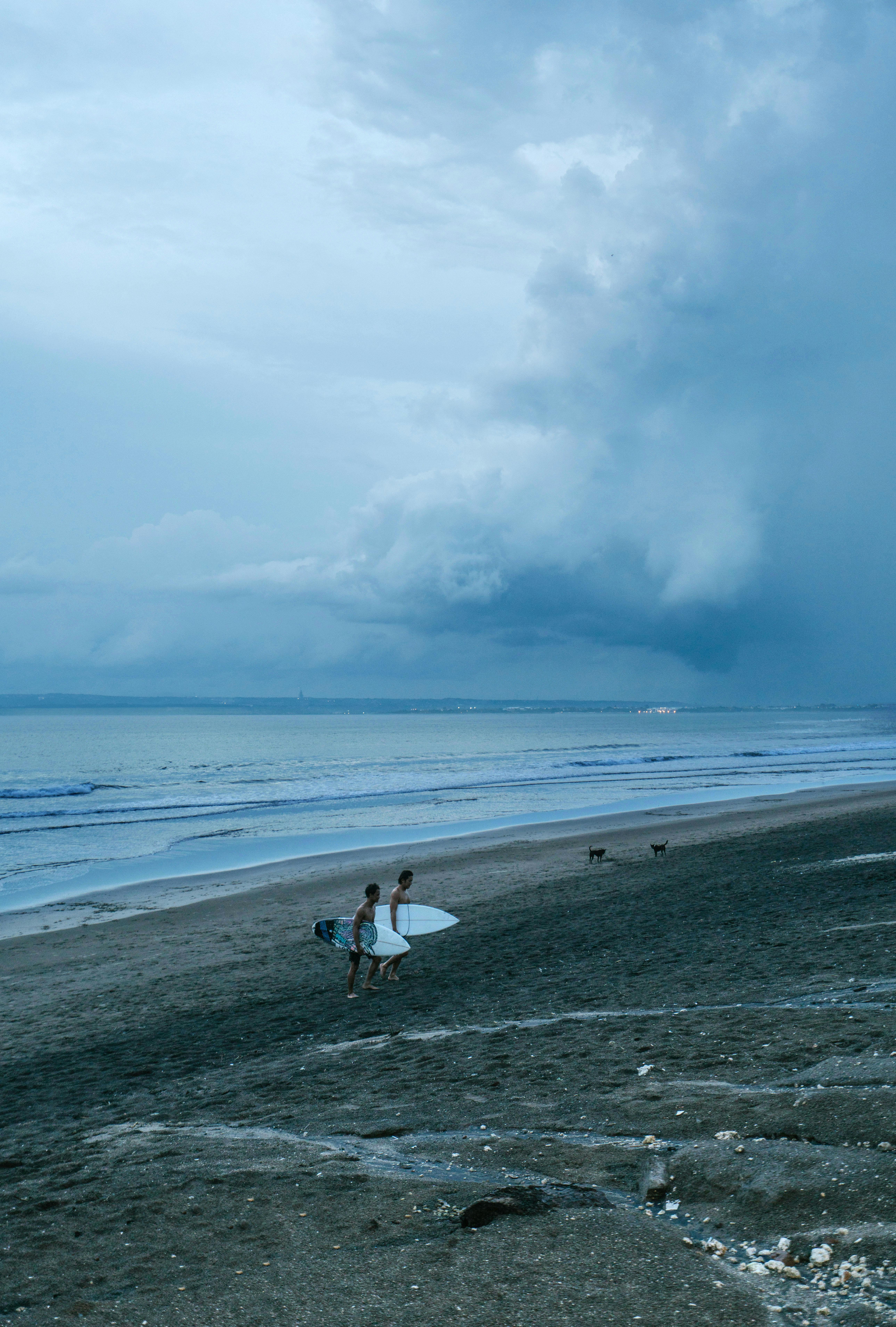 Surfers on ocean coast in cloudy day · Free Stock Photo