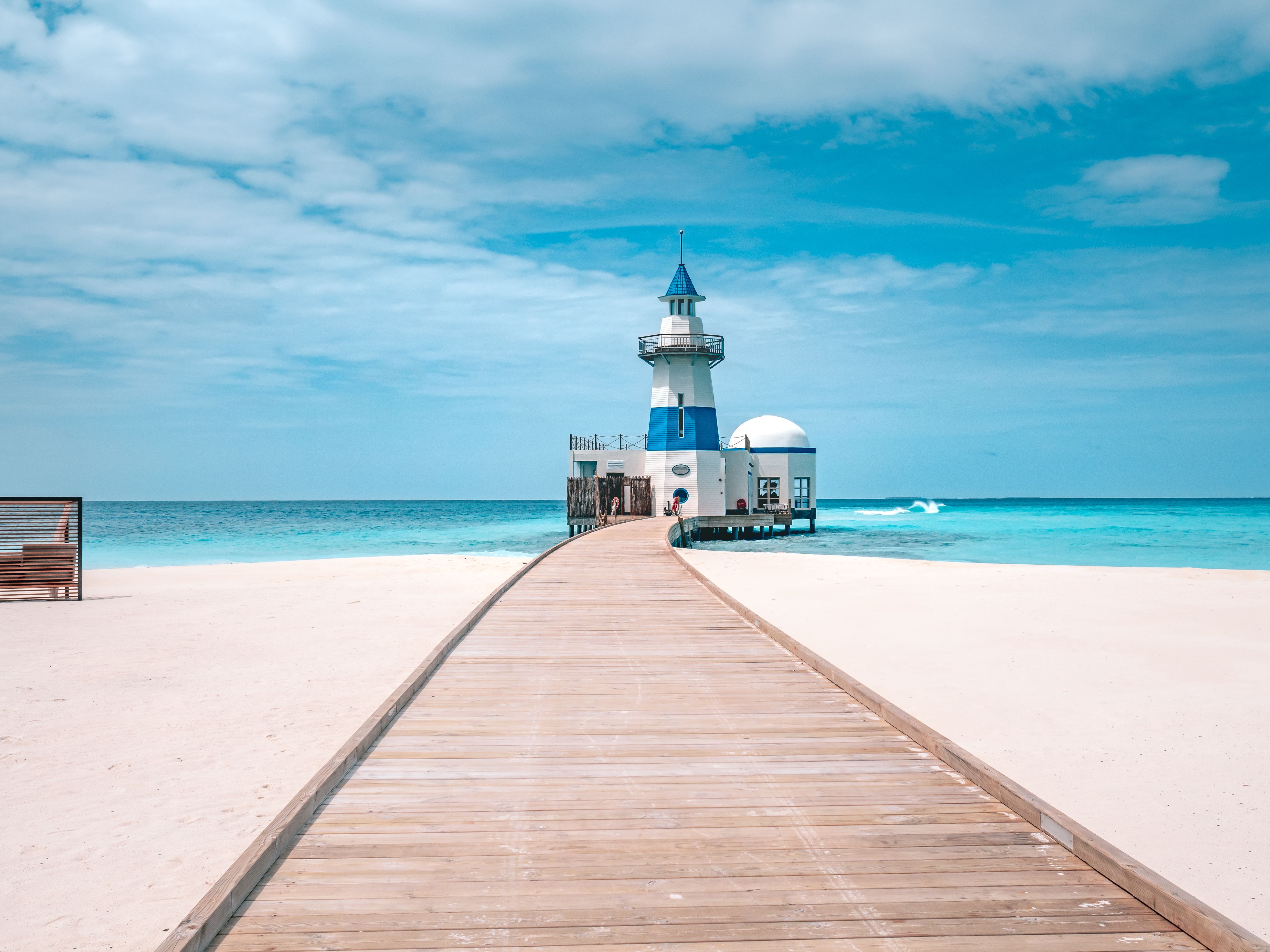 Wooden path to lighthouse in blue sea · Free Stock Photo