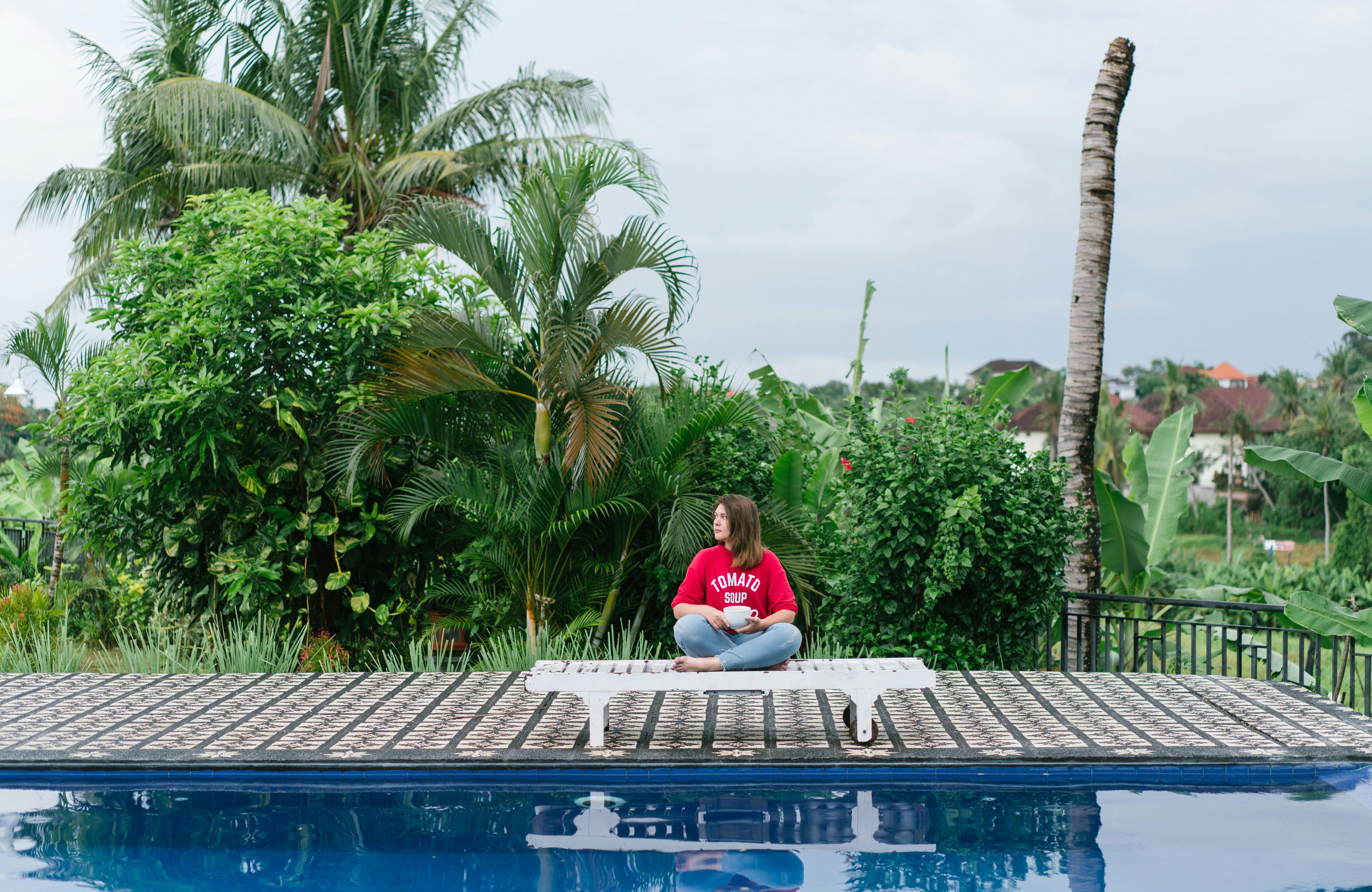 Woman relaxing on empty poolside of tropical resort · Free Stock Photo
