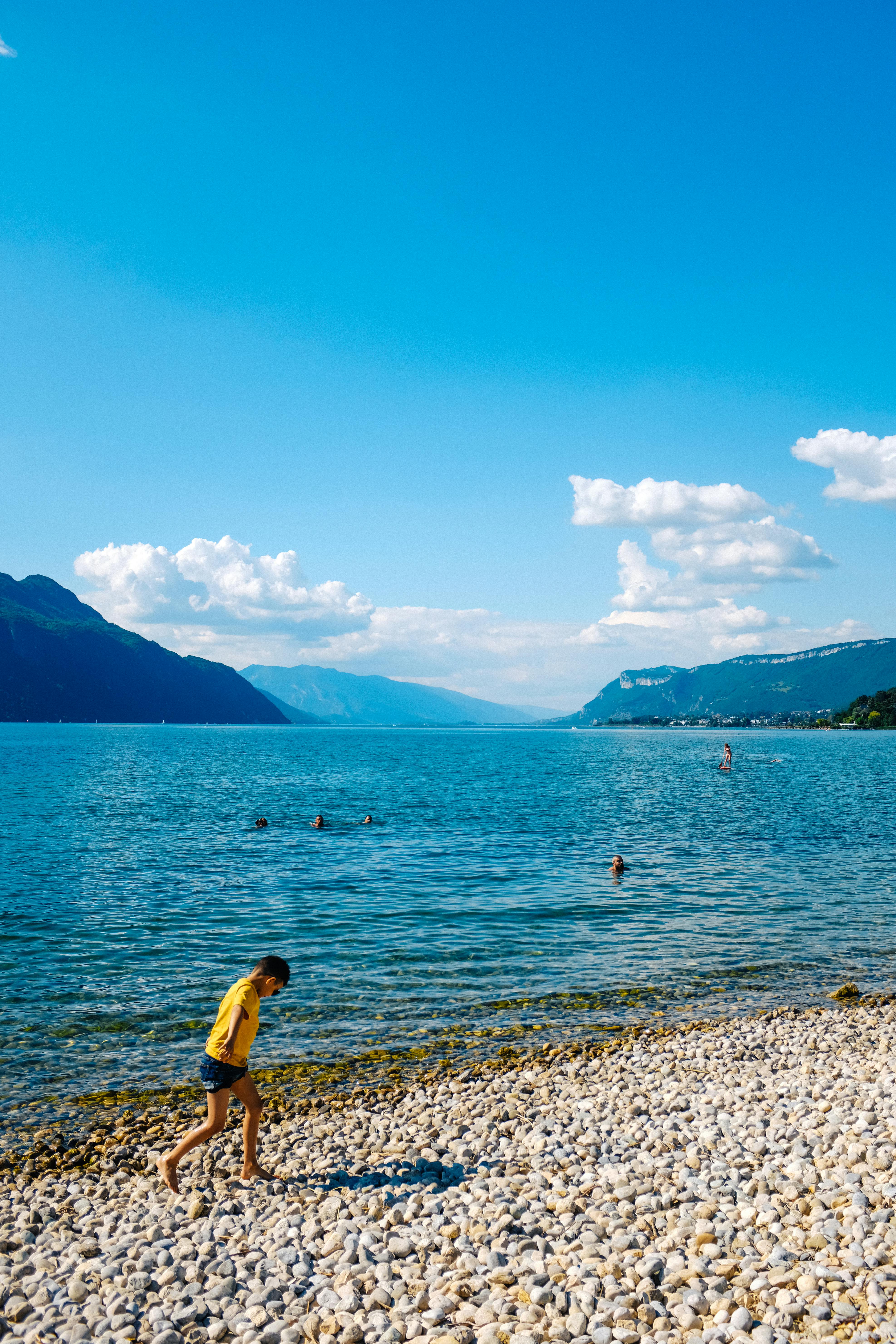 Positive female standing on stone on seaside · Free Stock Photo