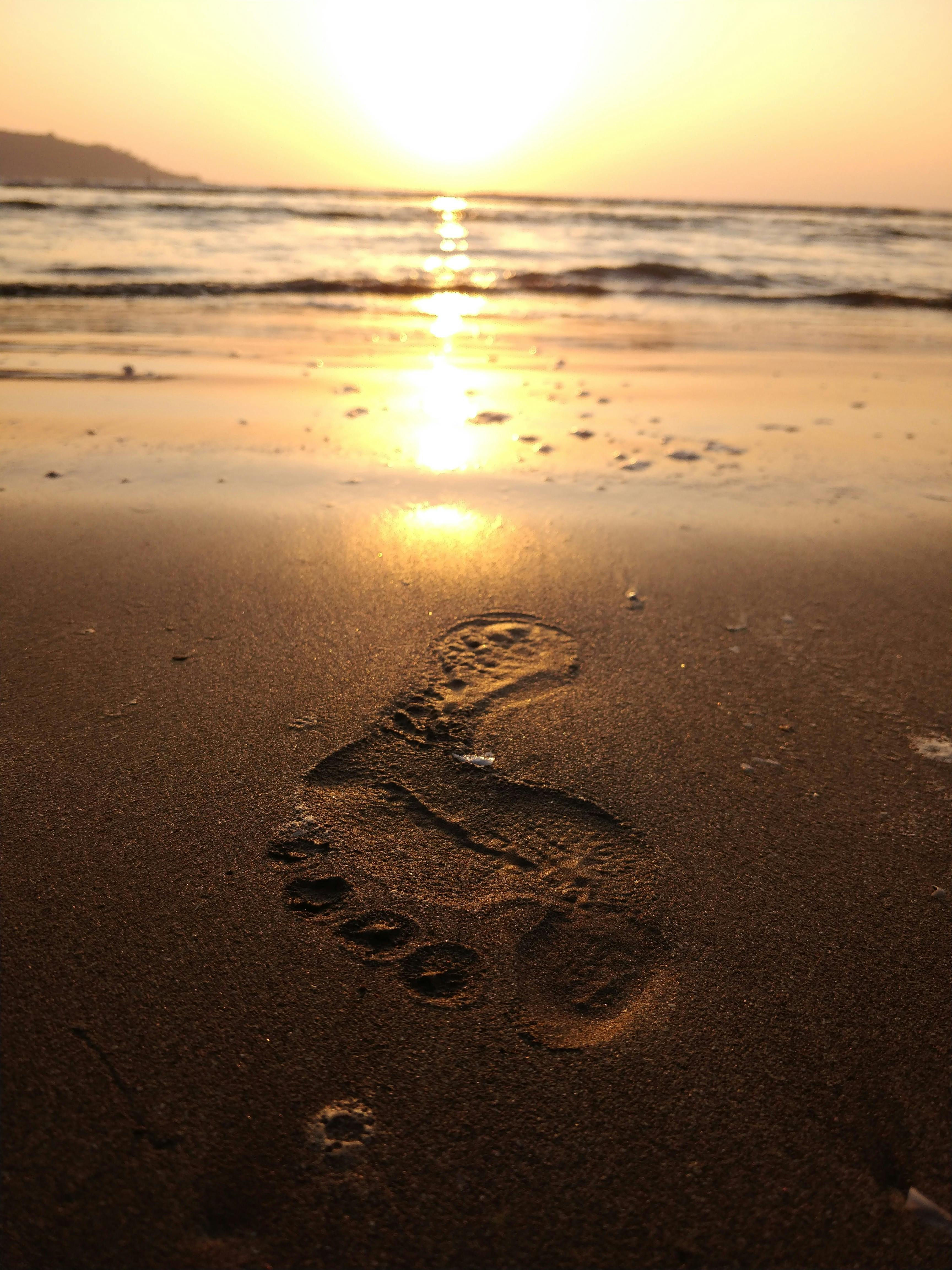 Footprint on sandy sea shore under glowing sky at sundown · Free Stock ...