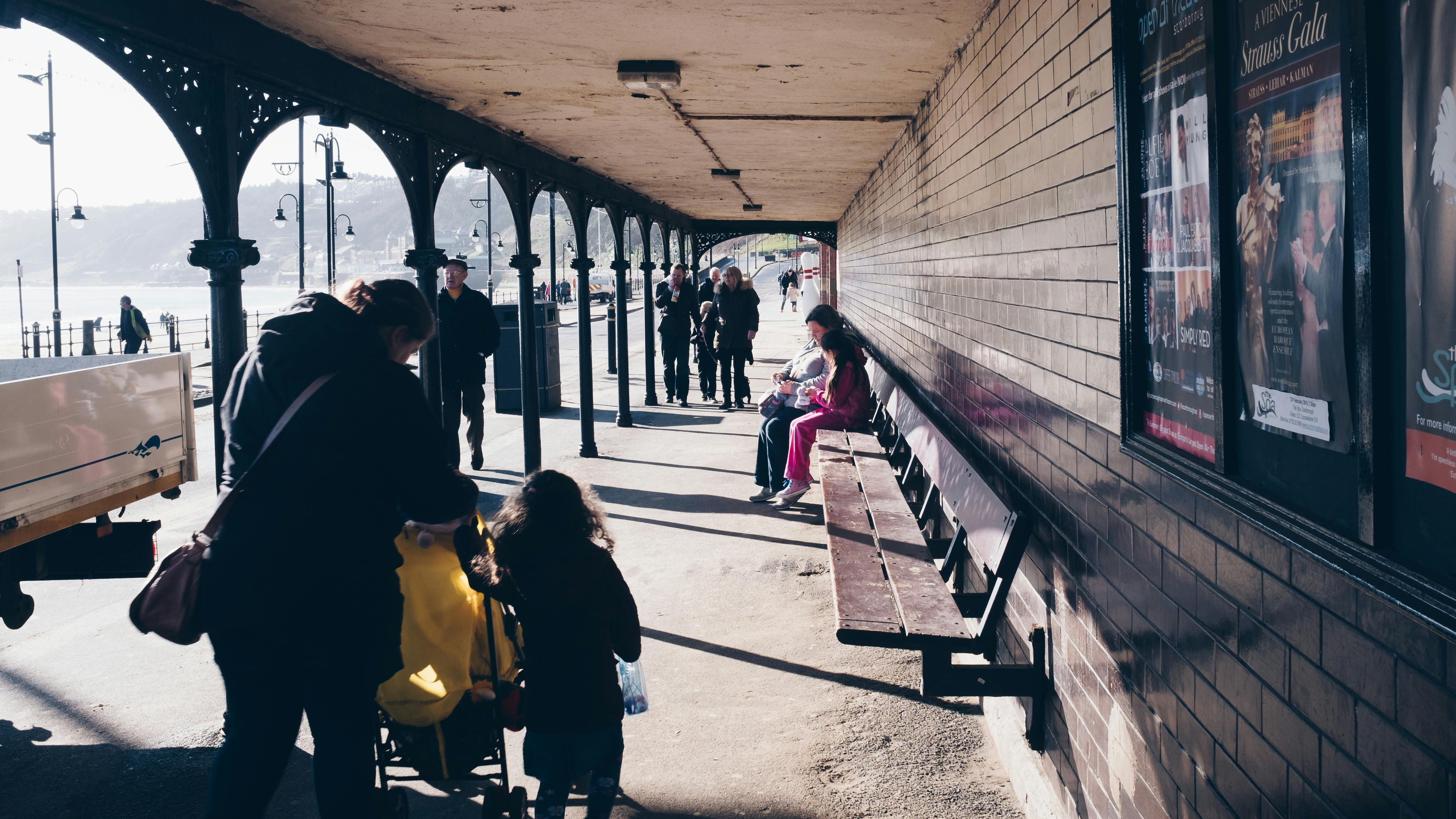 Anonymous people walking on arched pedestrian passage · Free Stock Photo