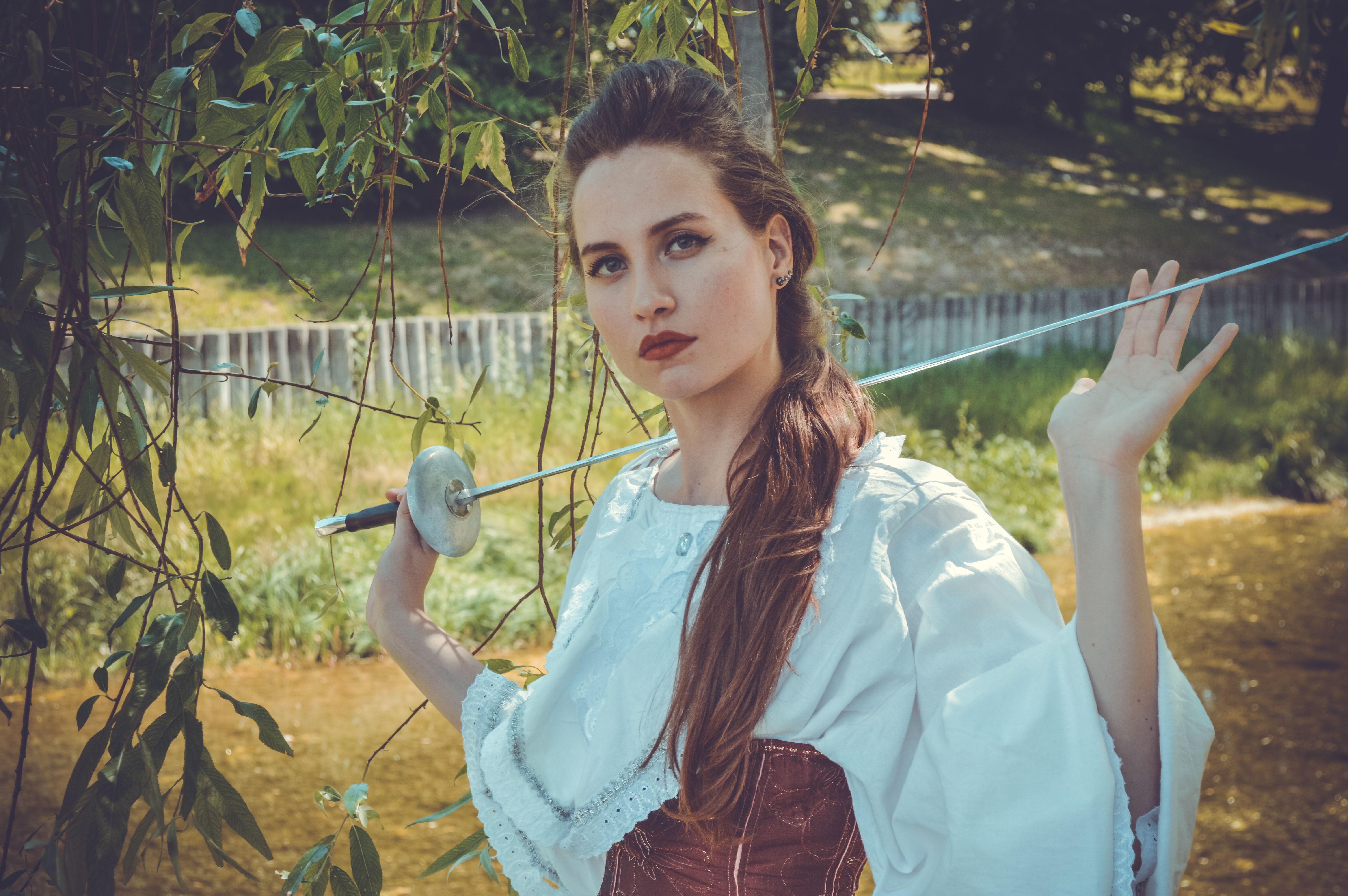 Focused young woman holding epee in hand and looking at camera · Free ...