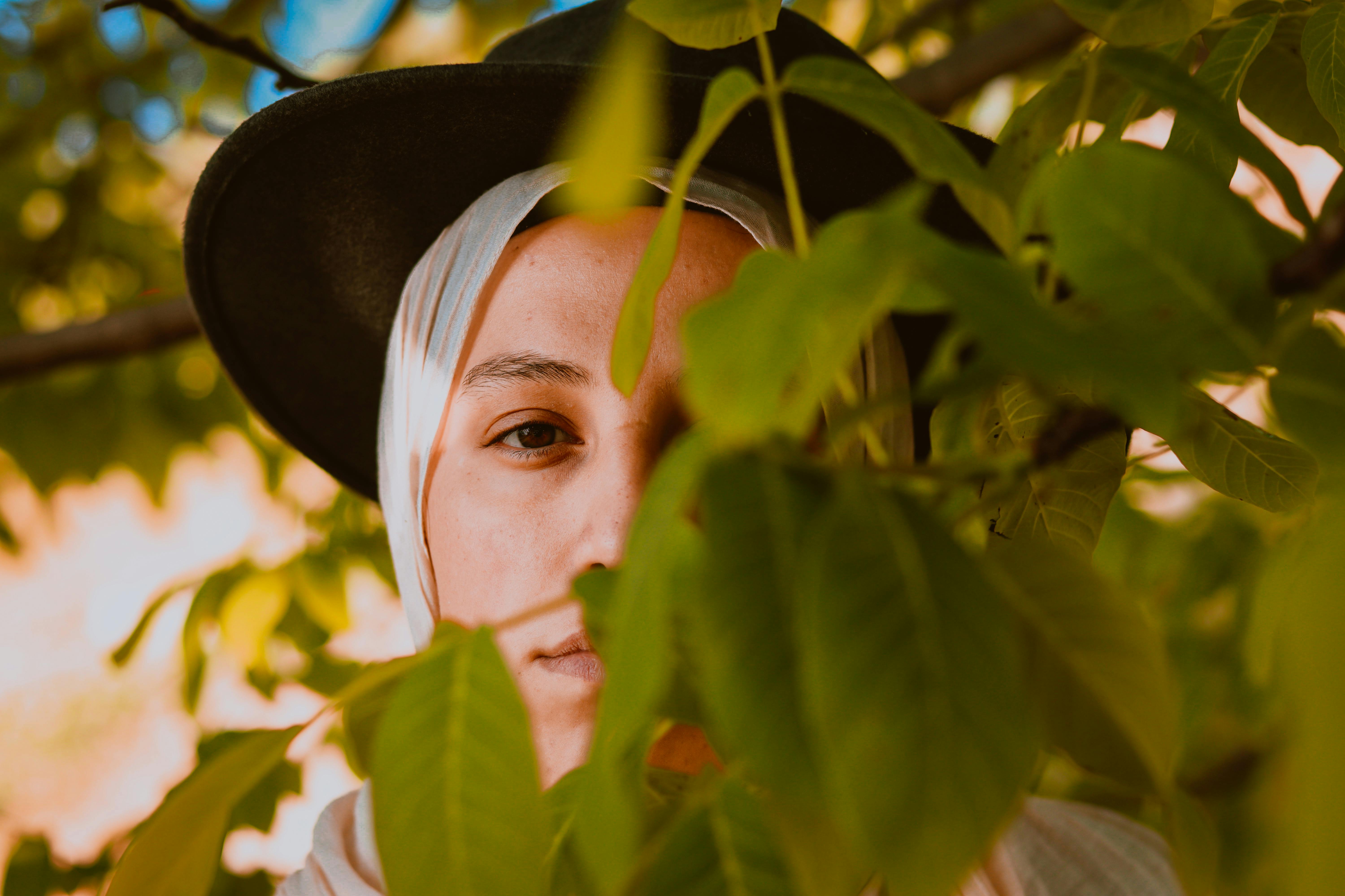 Pensive woman hiding behind tree branches · Free Stock Photo